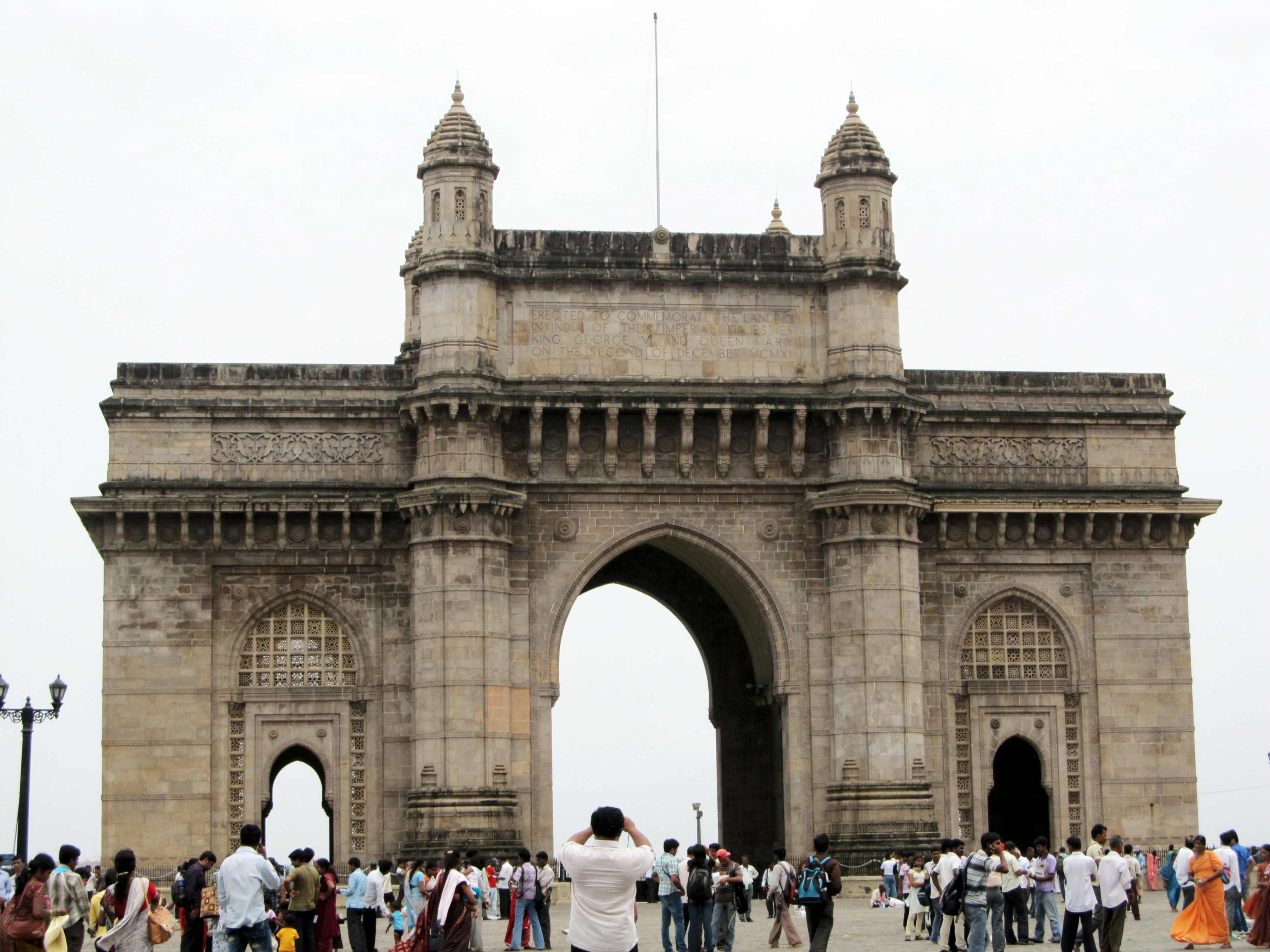 Iconic archway standing tall amidst a bustling crowd, showcasing the grandeur of the Gateway of India. The structure embodies historical significance and architectural beauty.
