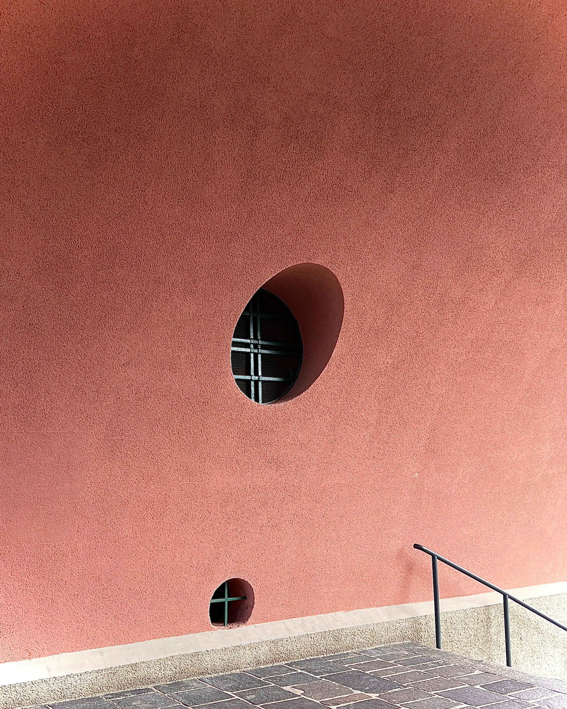 Emergent Circle: A Red Facade with Circular Windows and a Subtle Stair