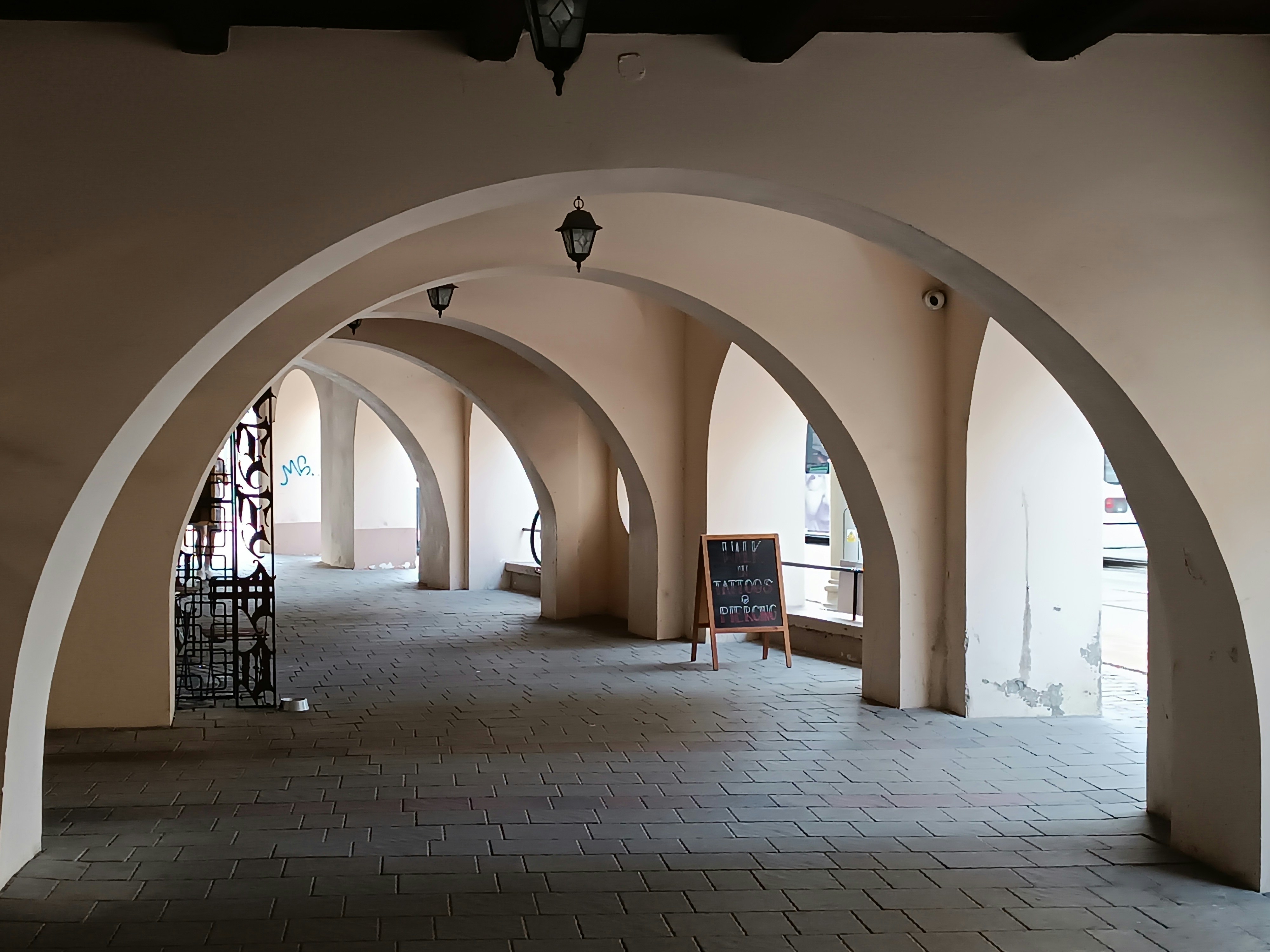 Series of beige arches casting soft shadows in a sunlit corridor.