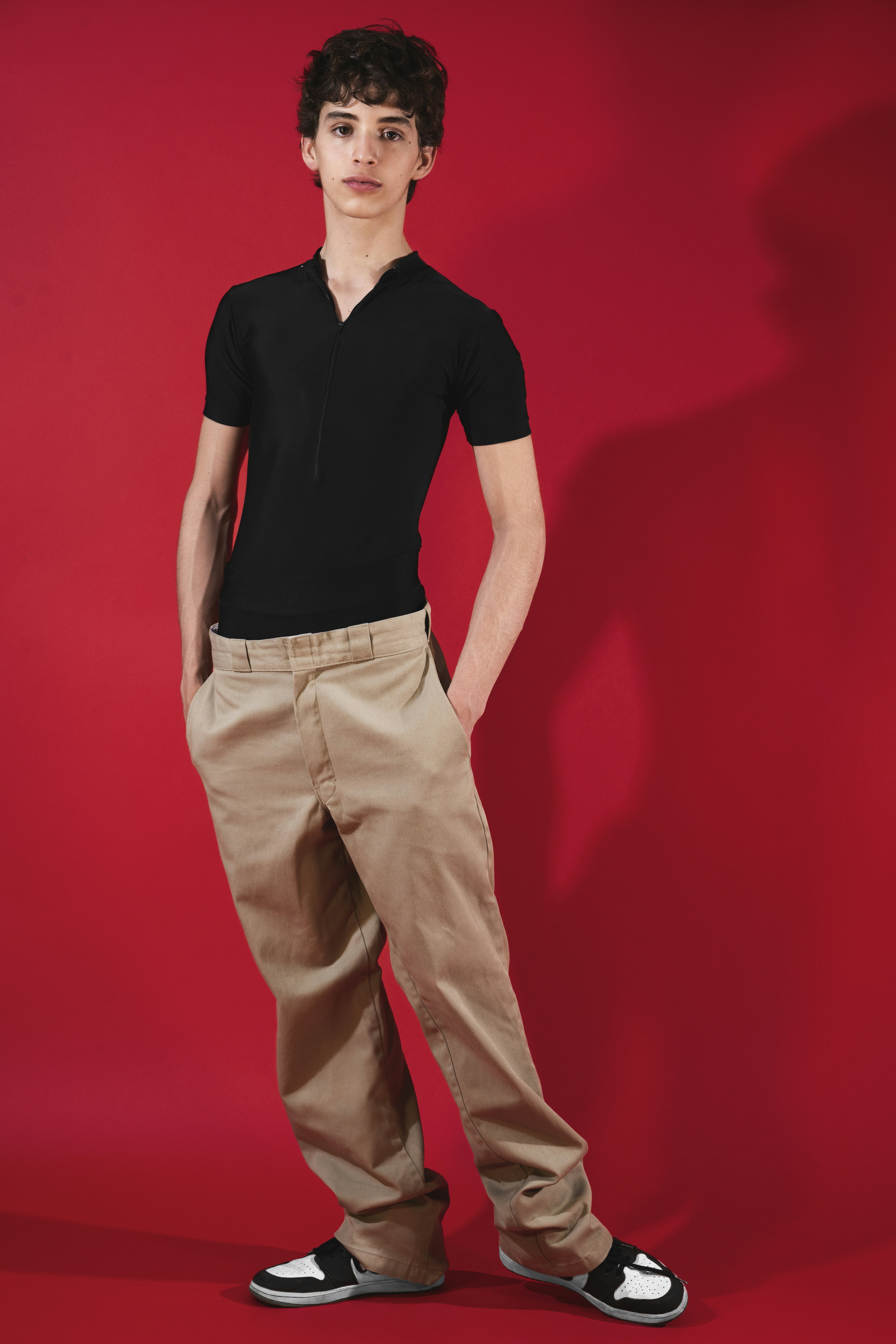 A young man standing in front of a red background