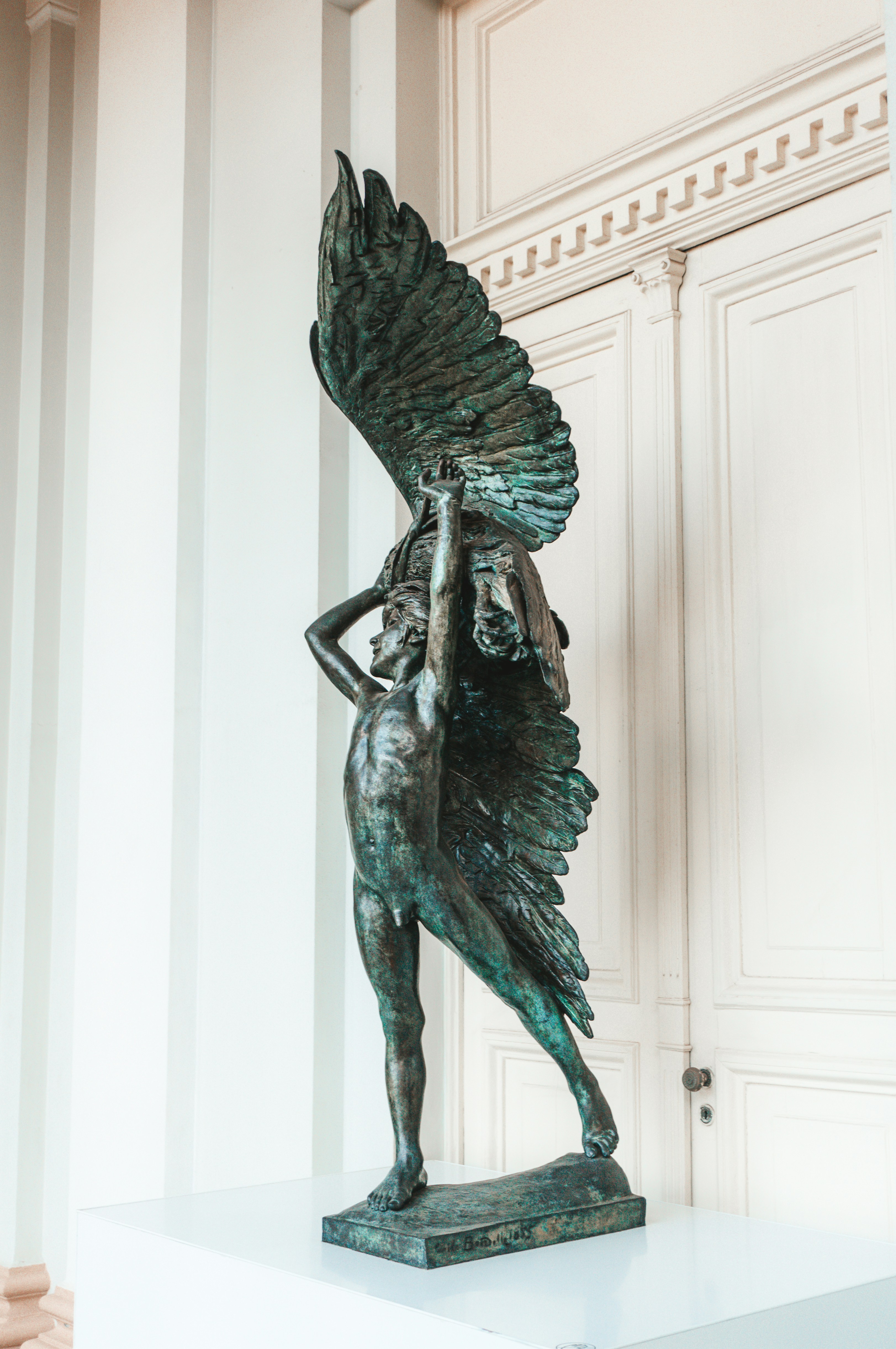 Winged Bronze: A Regal Statue Guarding a Pale Parlor Doorway