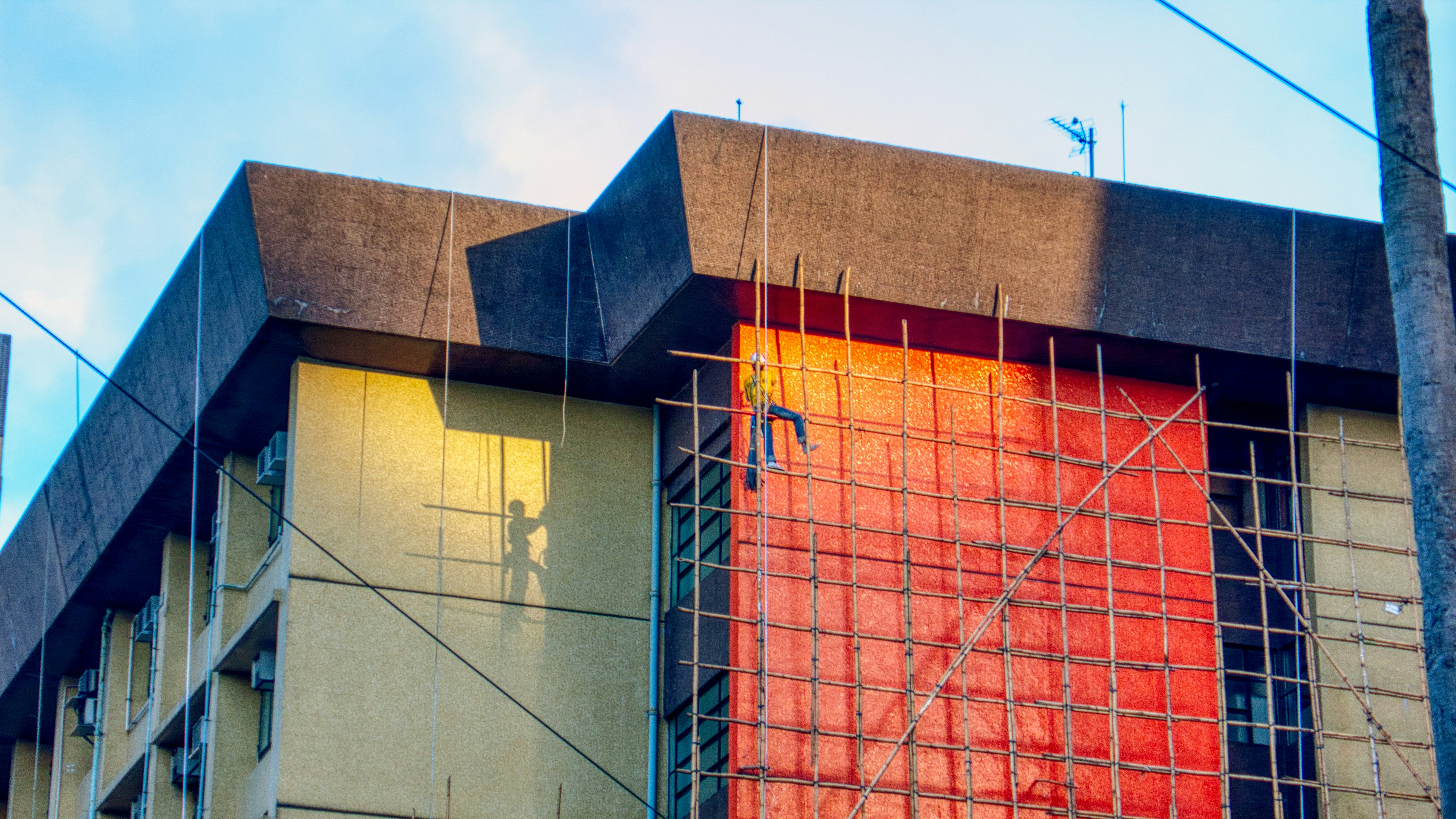 Shadowed Figure on a Color-Blocked Facade Under a Clear Sky
