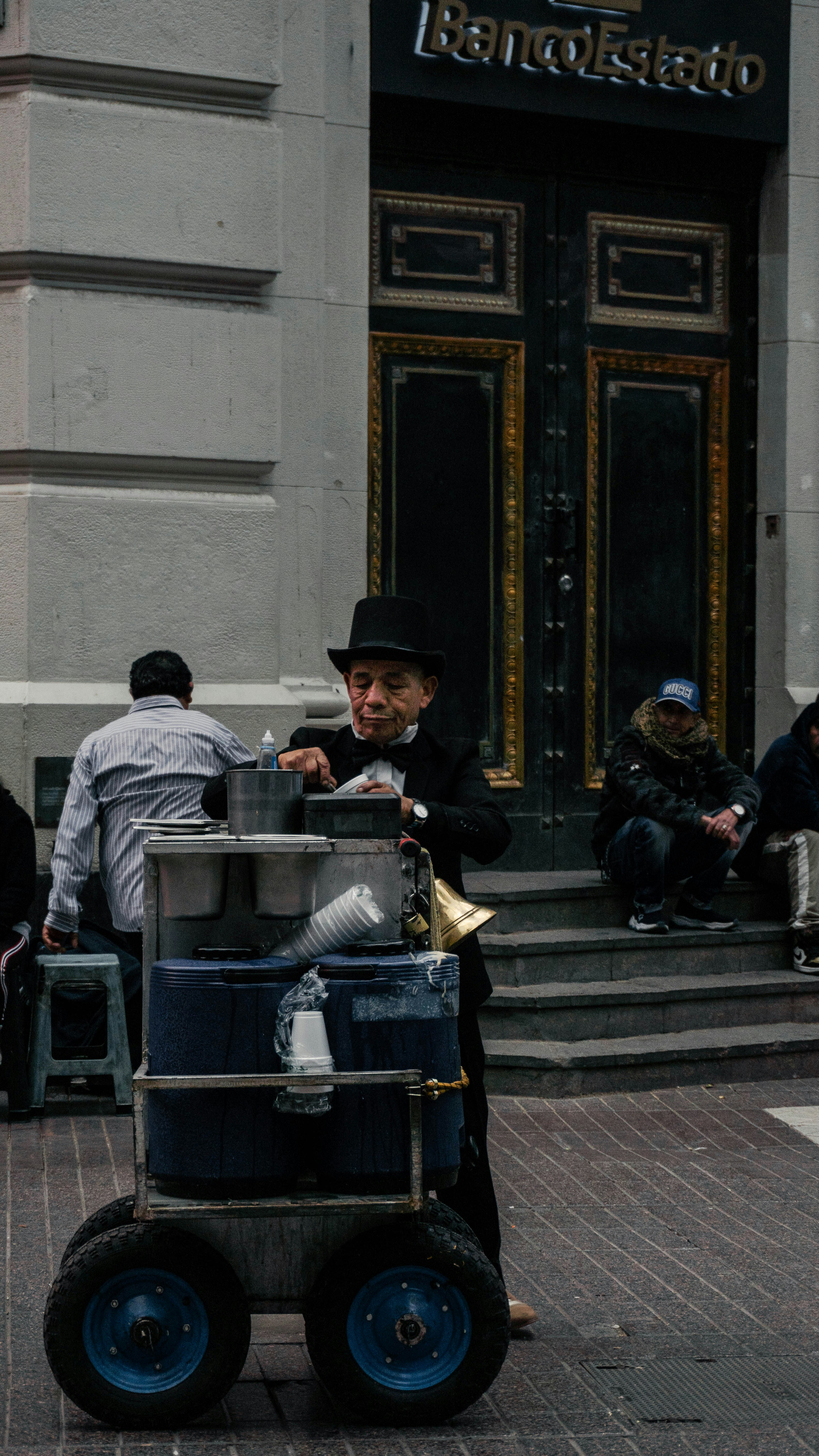 A man is sitting on a cart in front of a building
