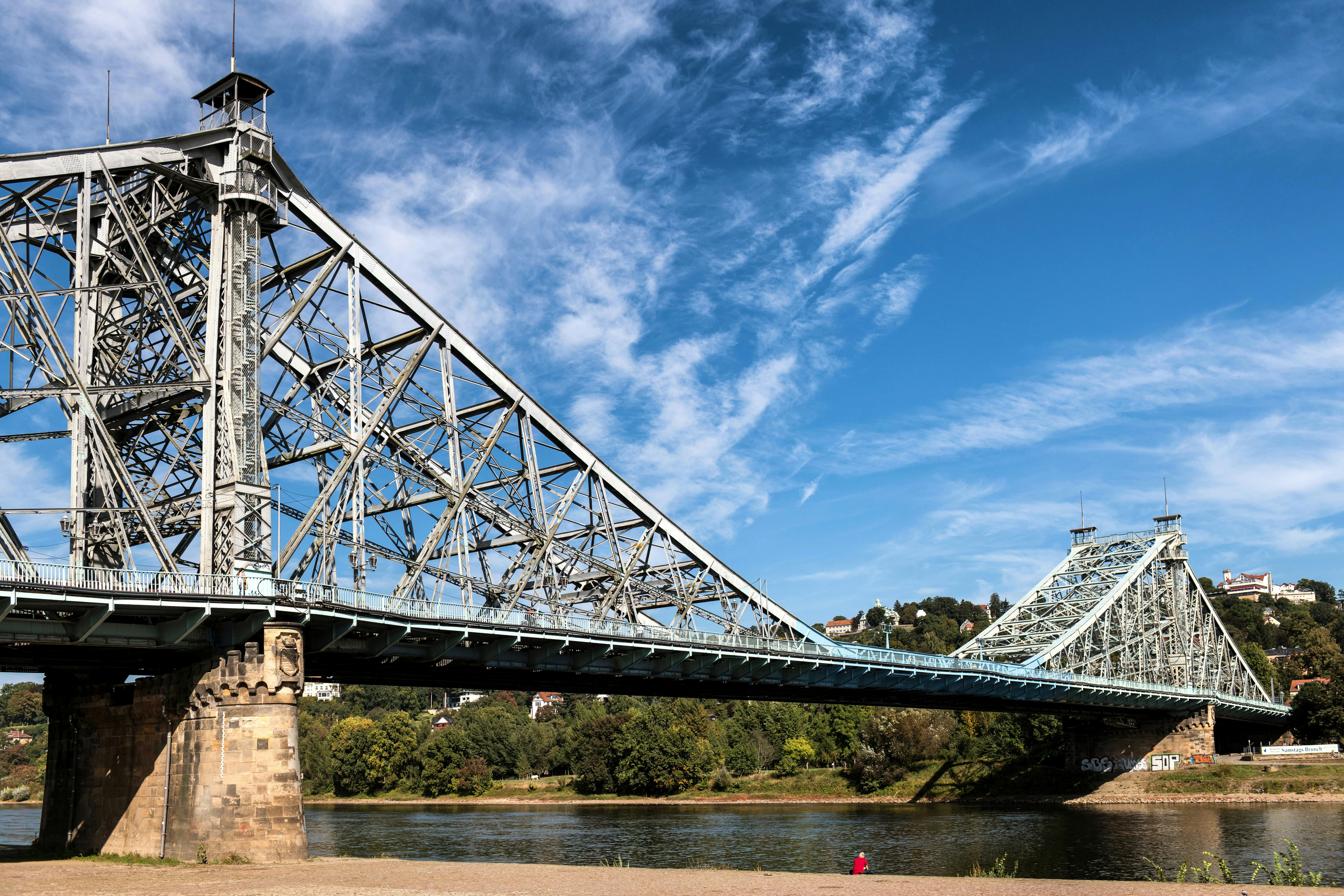 A large metal bridge over a river under a blue sky photo – Free ...