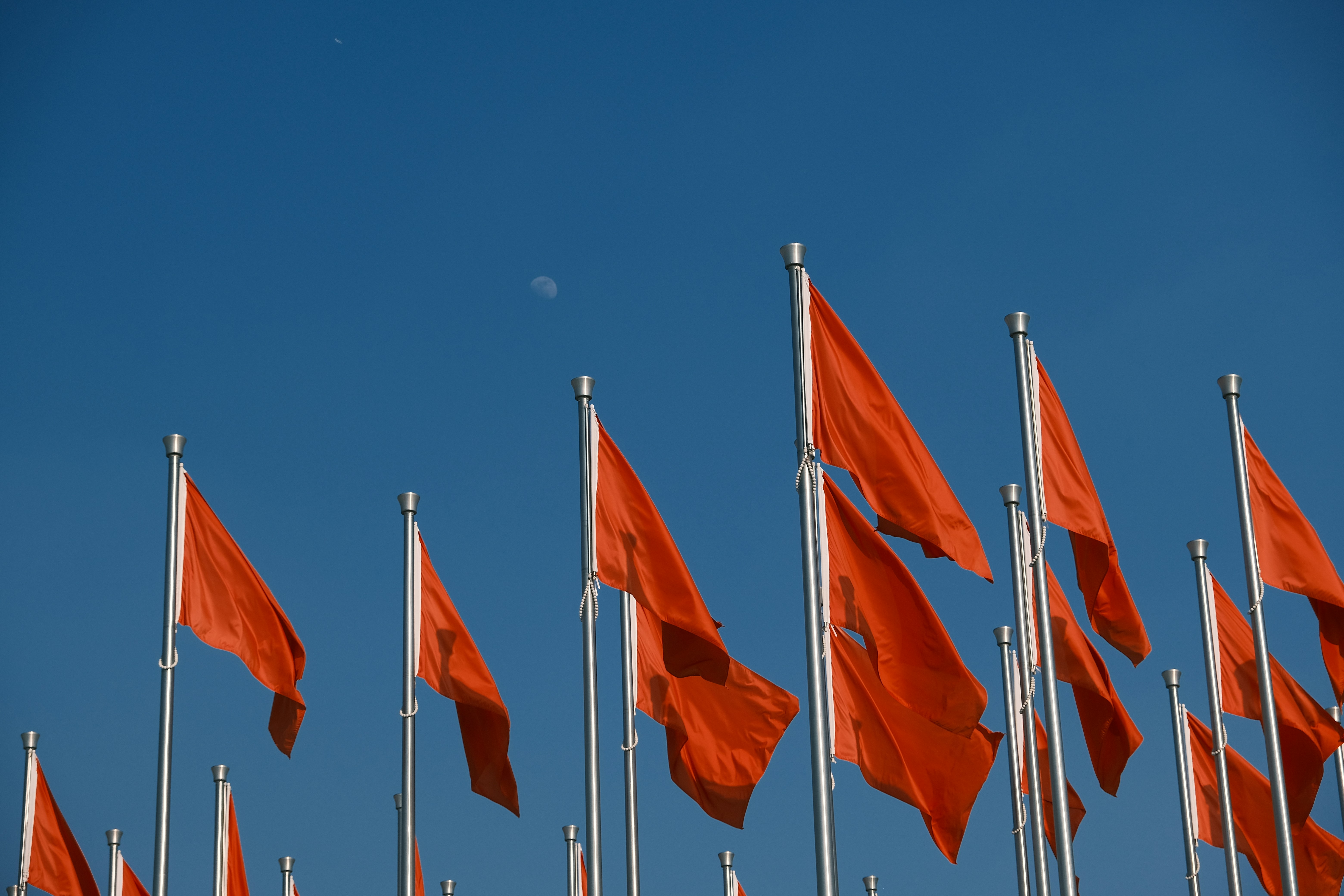A bunch of red flags flying in the wind photo – Free Flag Image on Unsplash