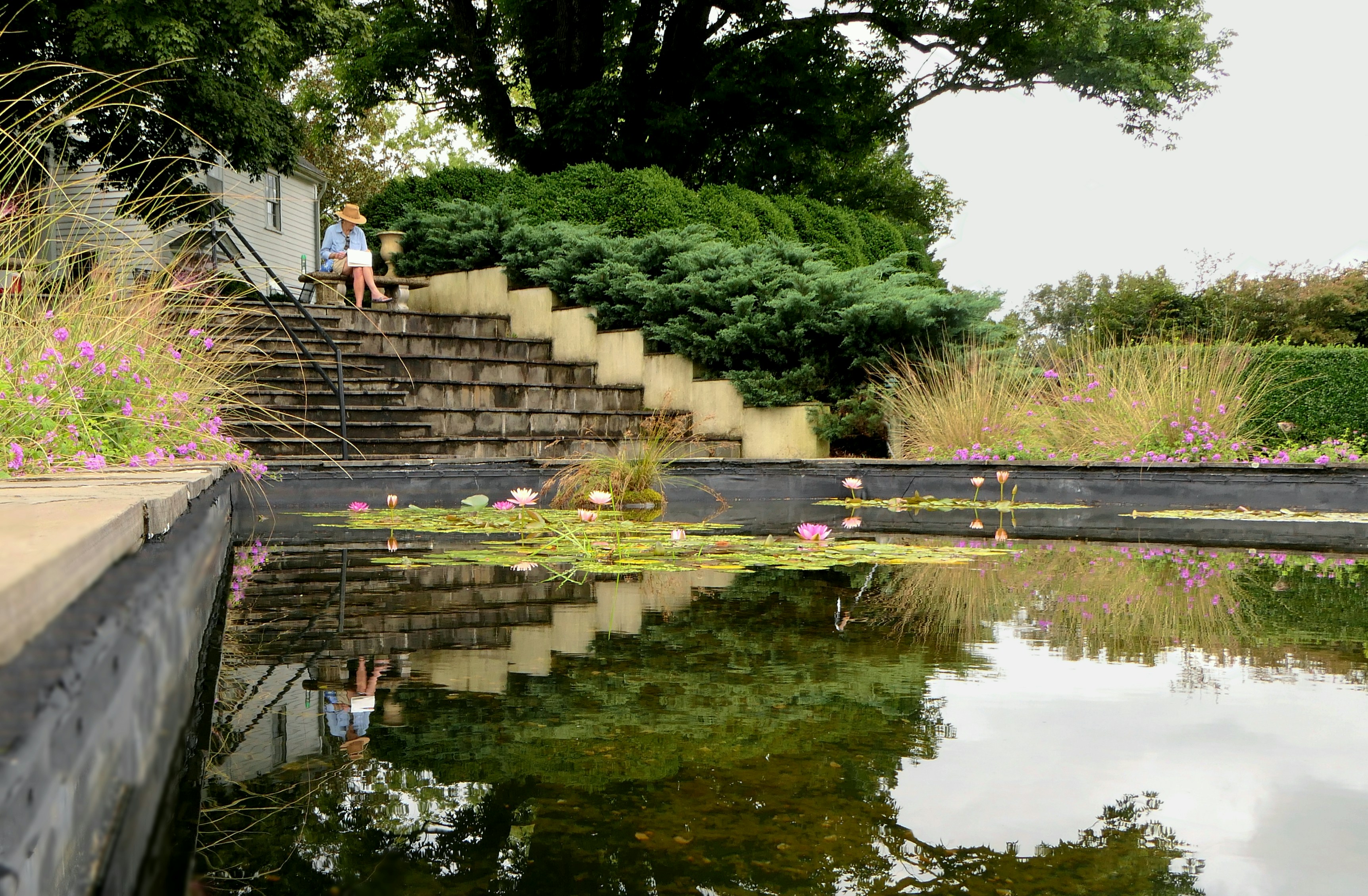 Artist on stairs reflected in pool