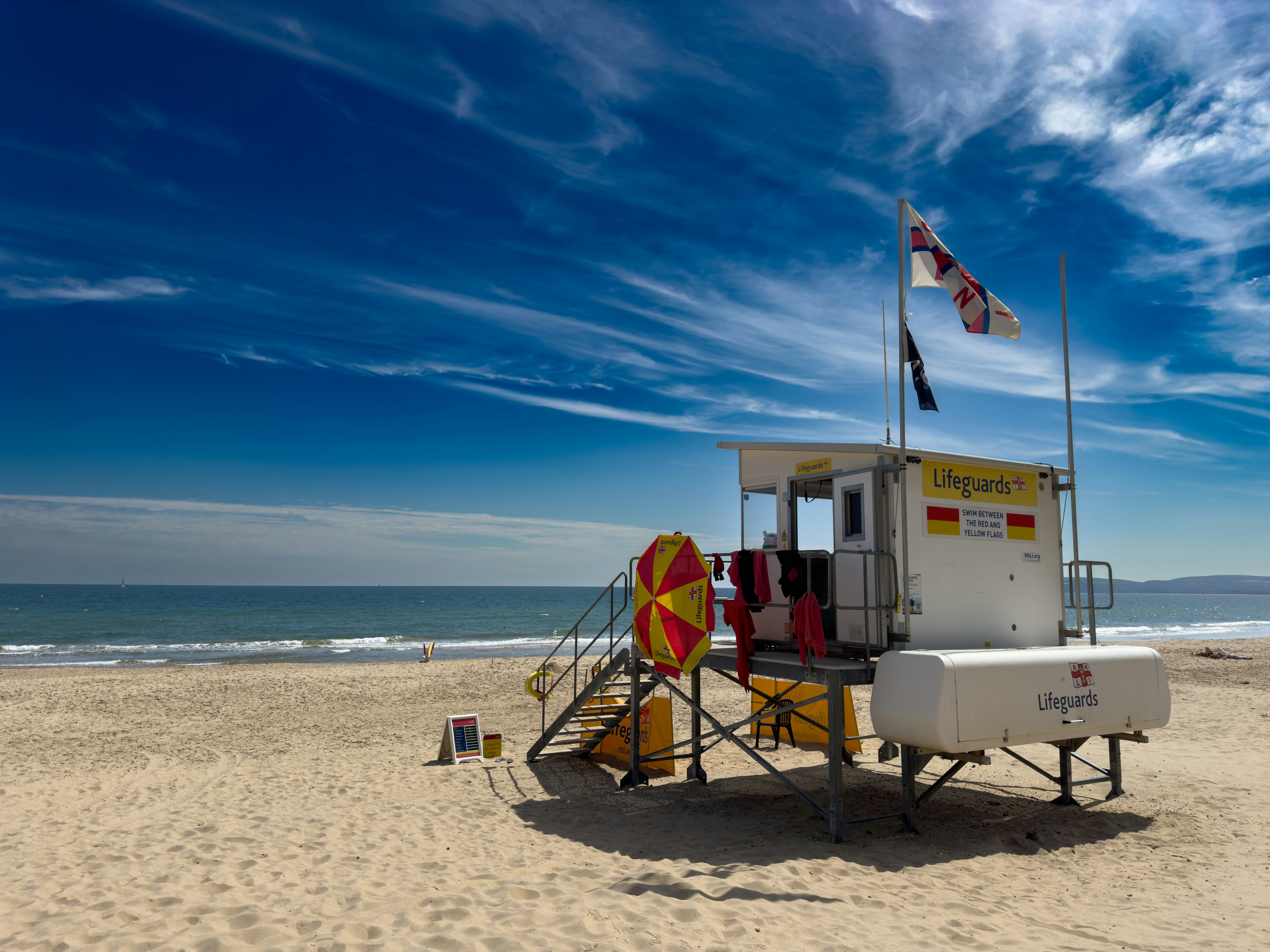 A lifeguard stand on the beach with a lifeguard flag photo – Free Alum ...
