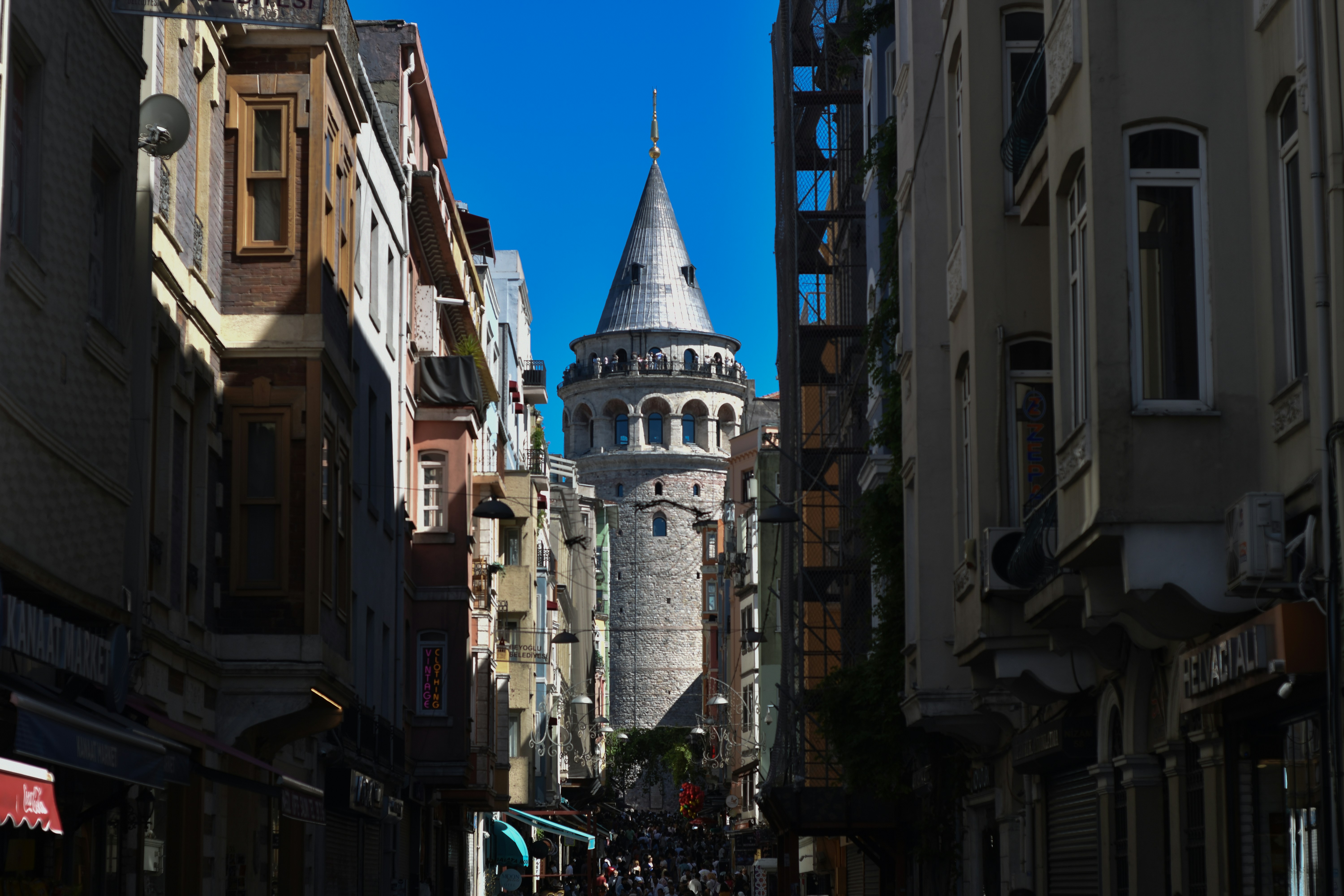 A narrow city street with a tower in the background