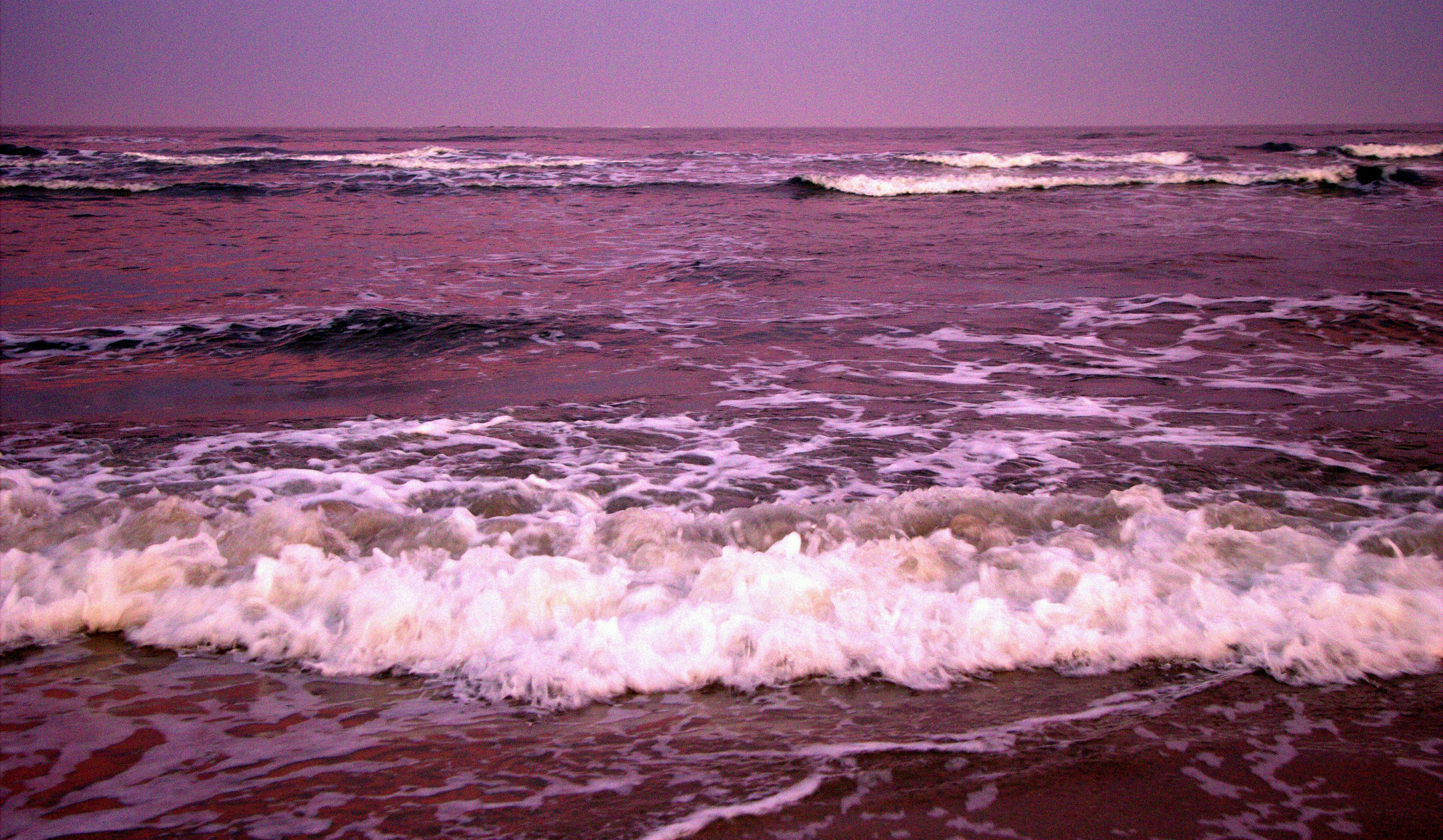 Un océan violet avec des vagues arrivant sur le rivage photo – Image ...