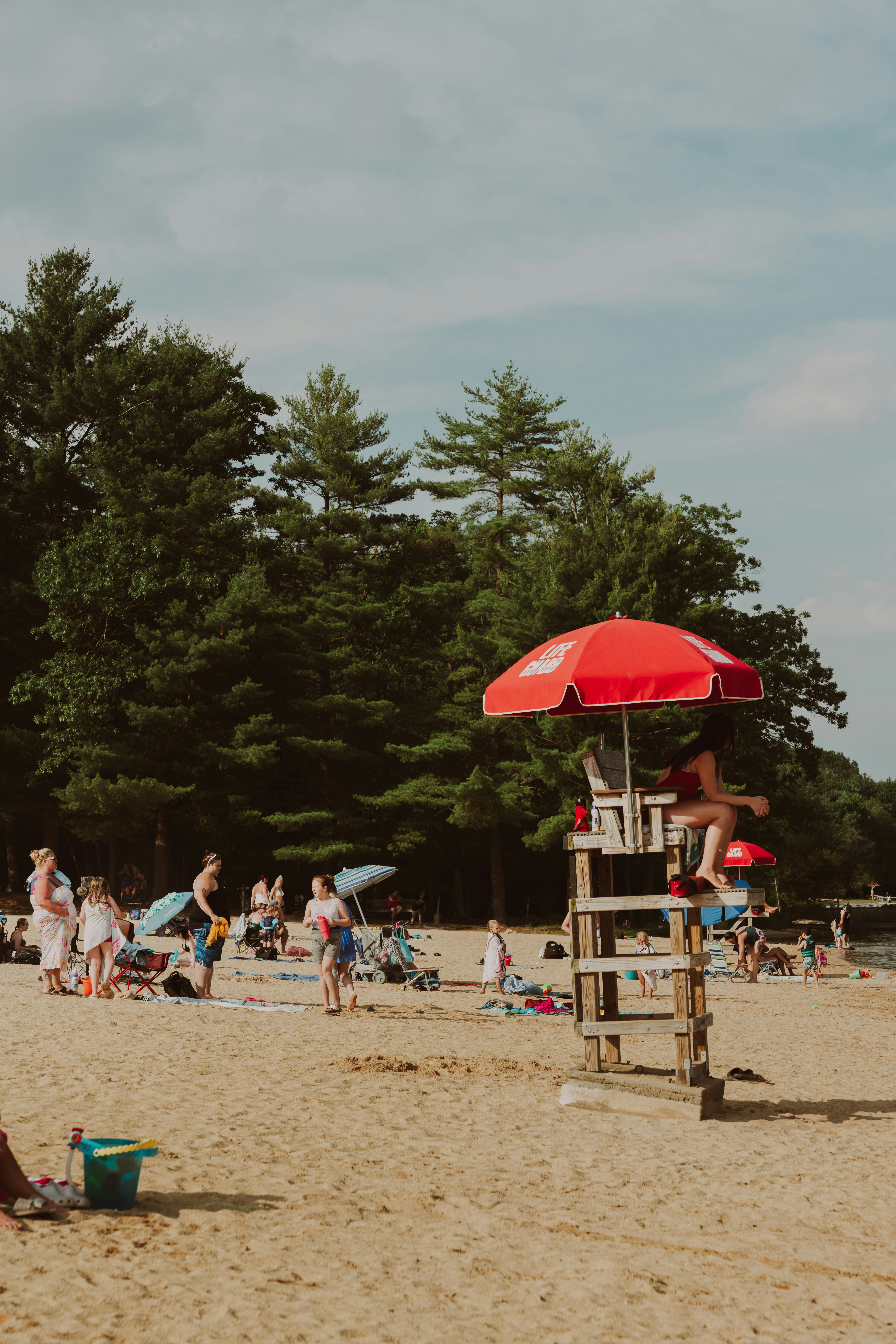 Crimson Umbrella Anchors a Lifeguard Stand on a Bustling Beach