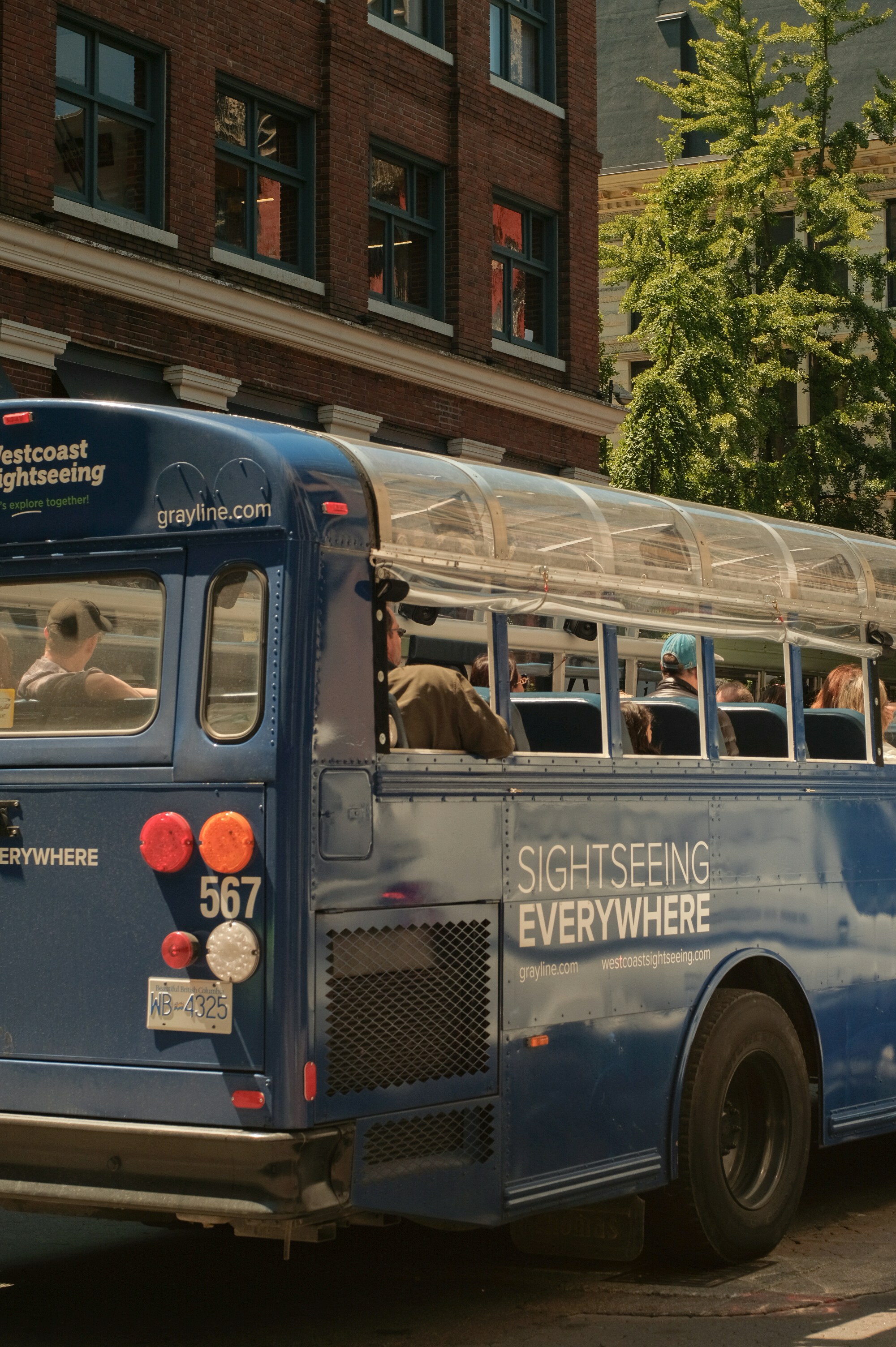 A blue bus driving down a street next to tall buildings
