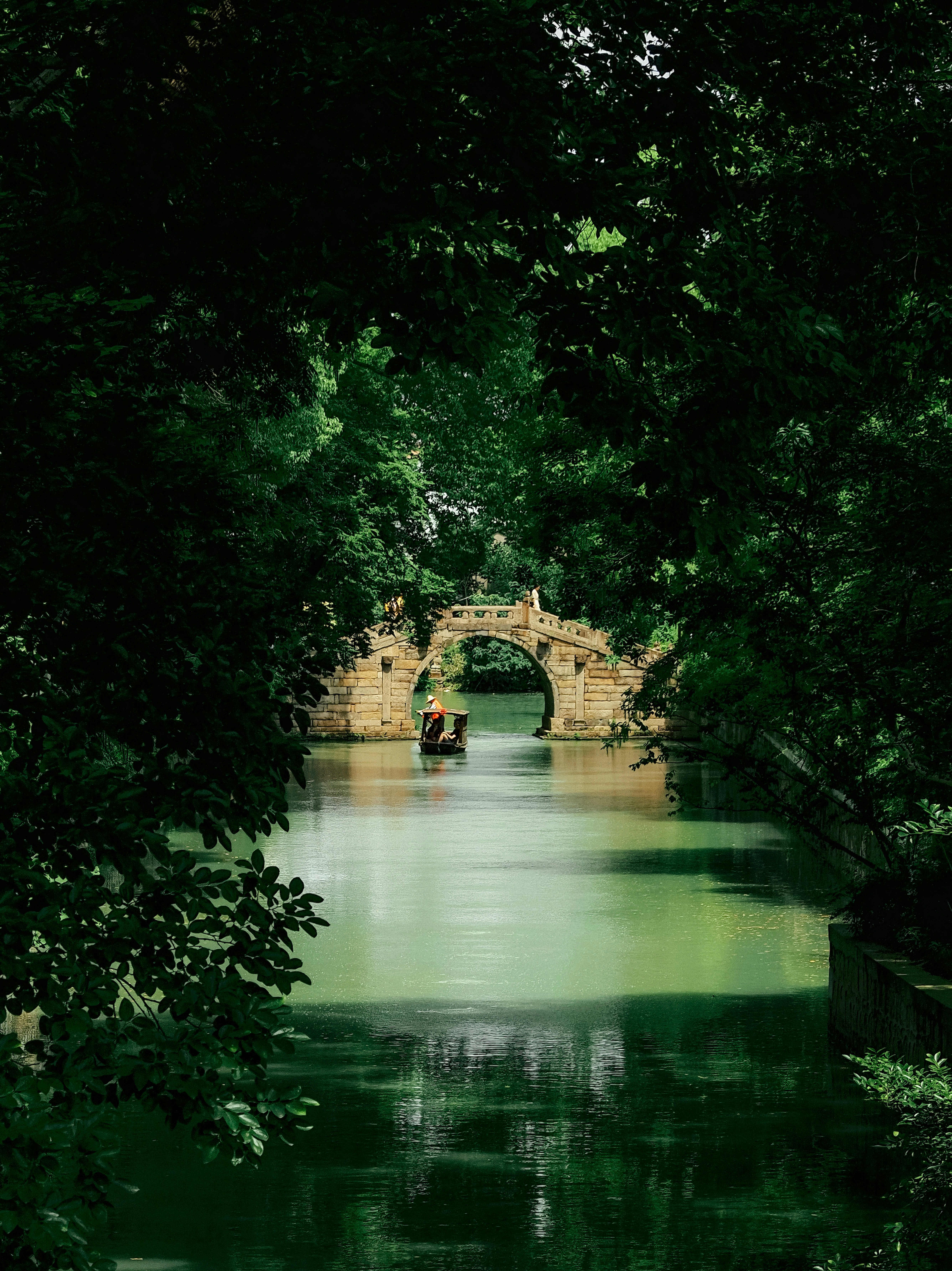 Ivy-Framed Arch Over a Verdant River with a Quiet Boat