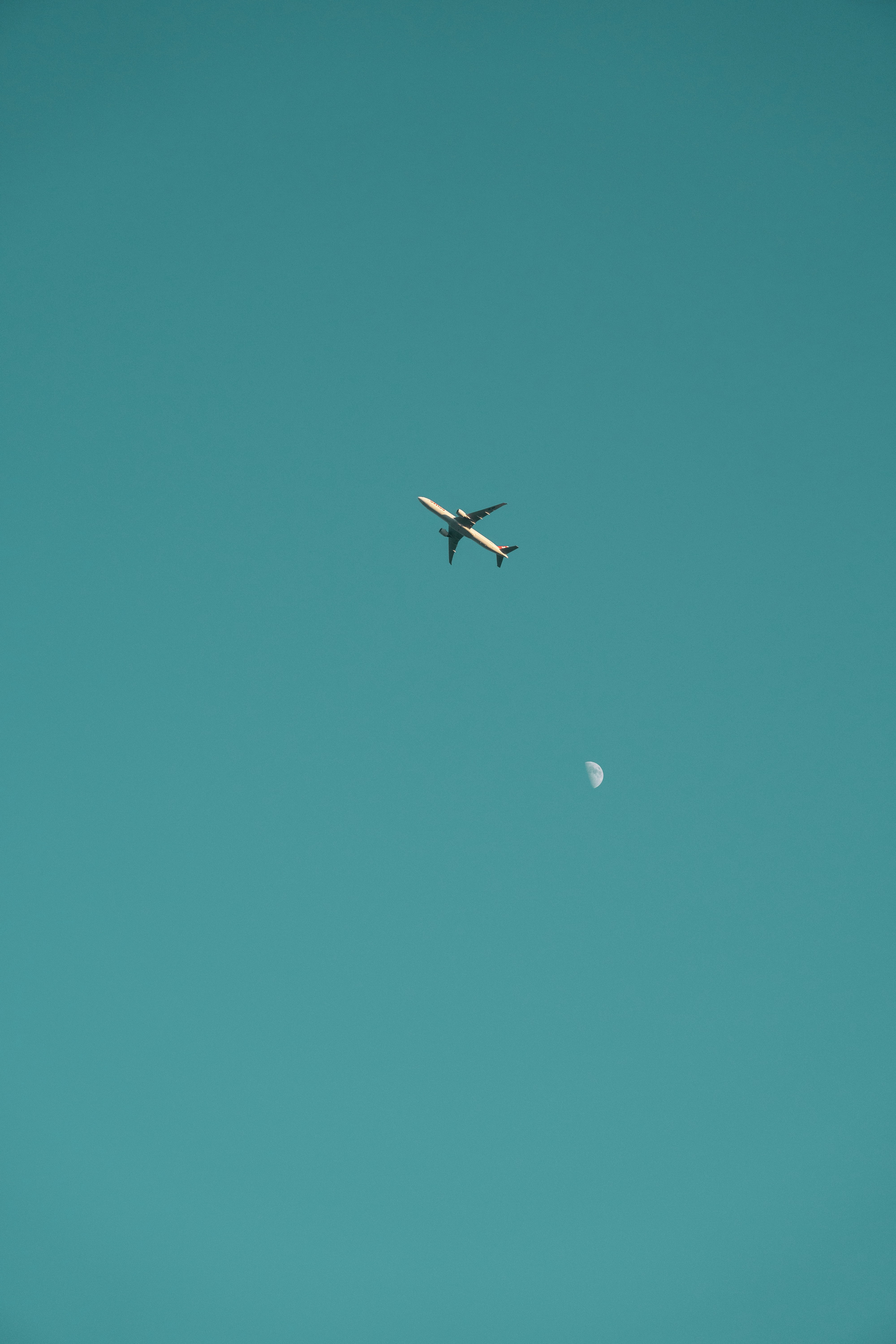 Teal Skyflight: A lone airliner under a crescent moon