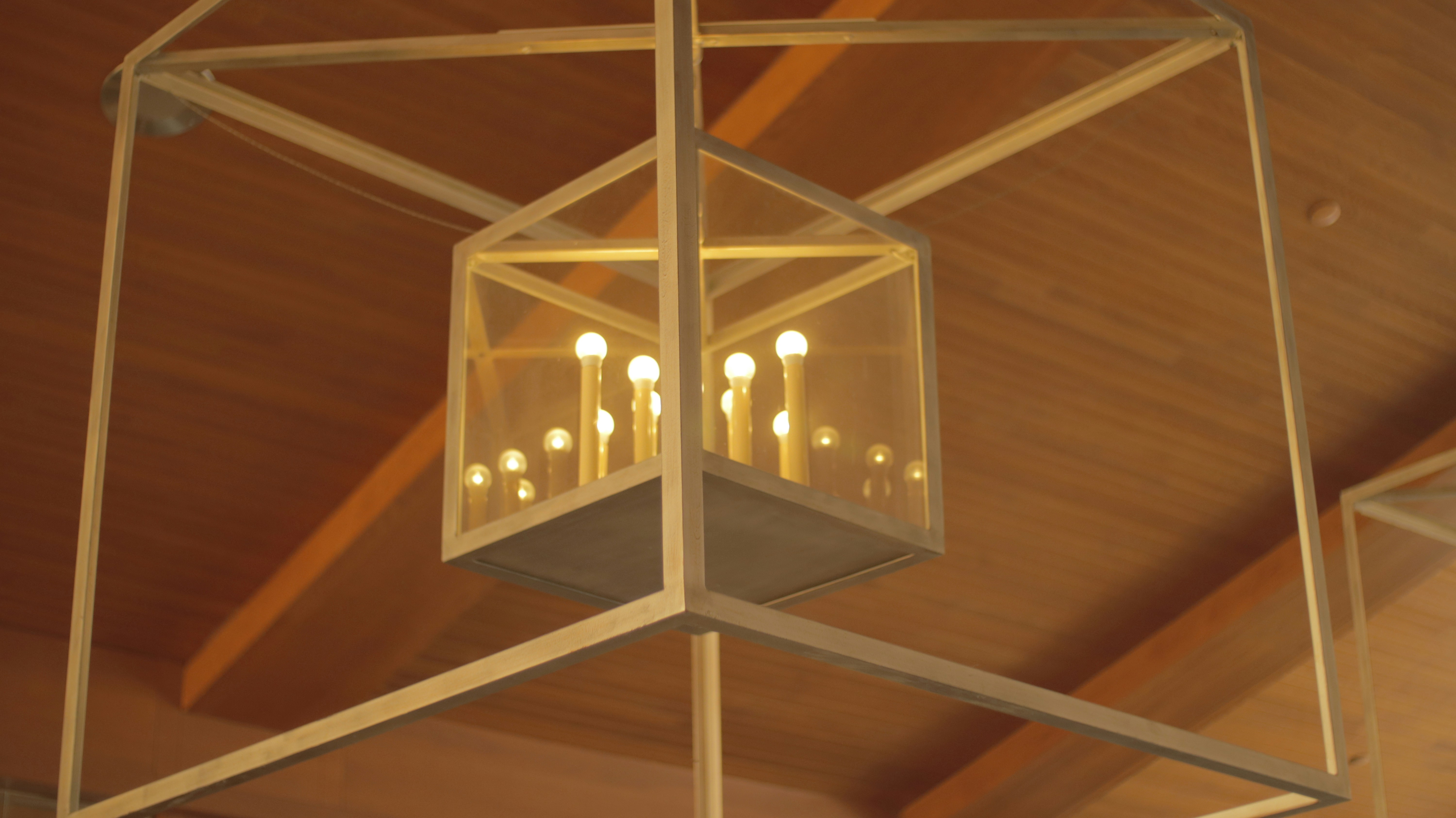 Geometric chandelier frame encasing a softly lit lanterns