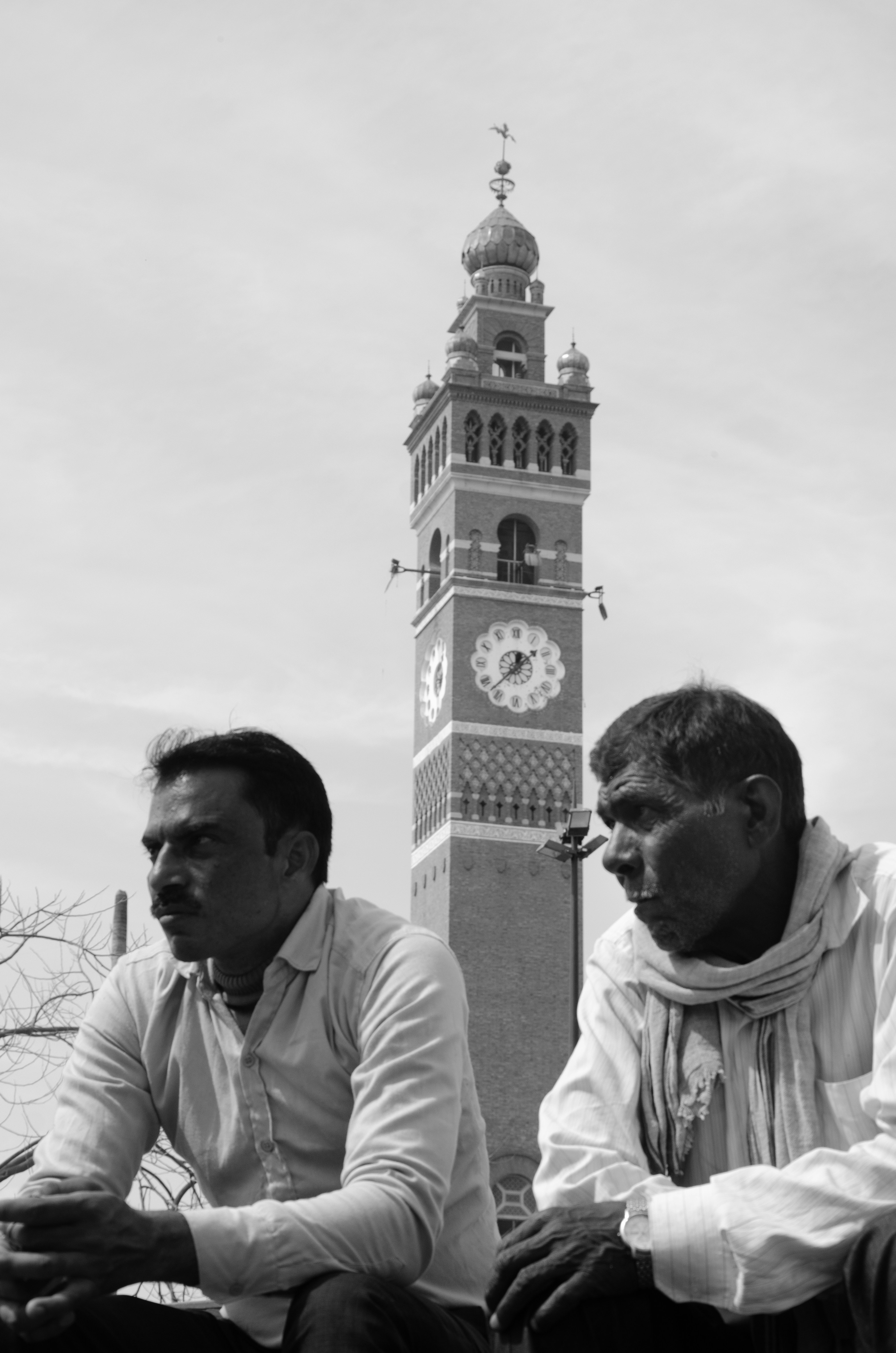 Time Beneath the Tower: Two Men in Conversation Before a Monolithic Clock Tower