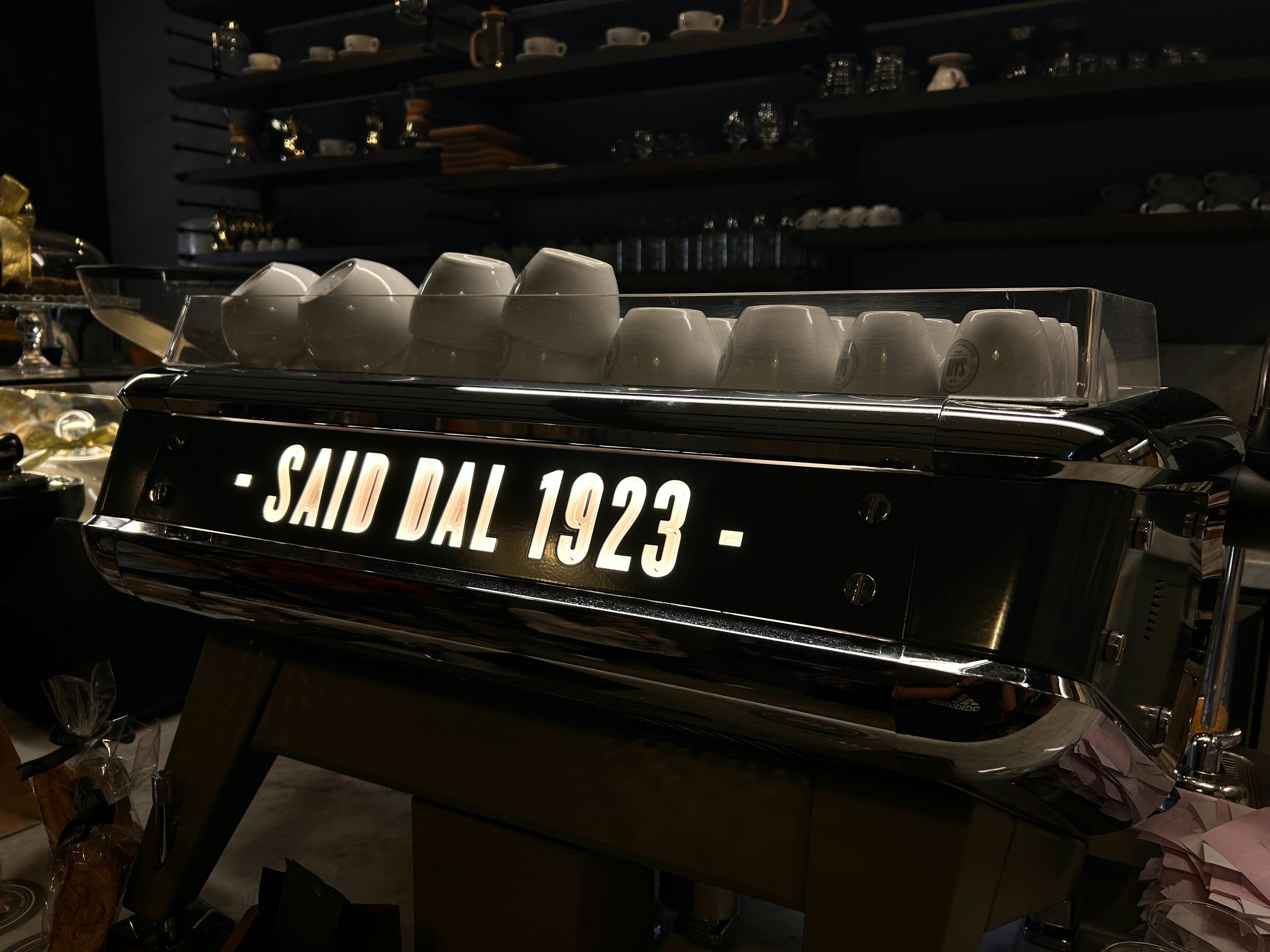 Chrome Café Echo: SAID DAL 1923 Espresso Machine Under Warm Shelf Light
