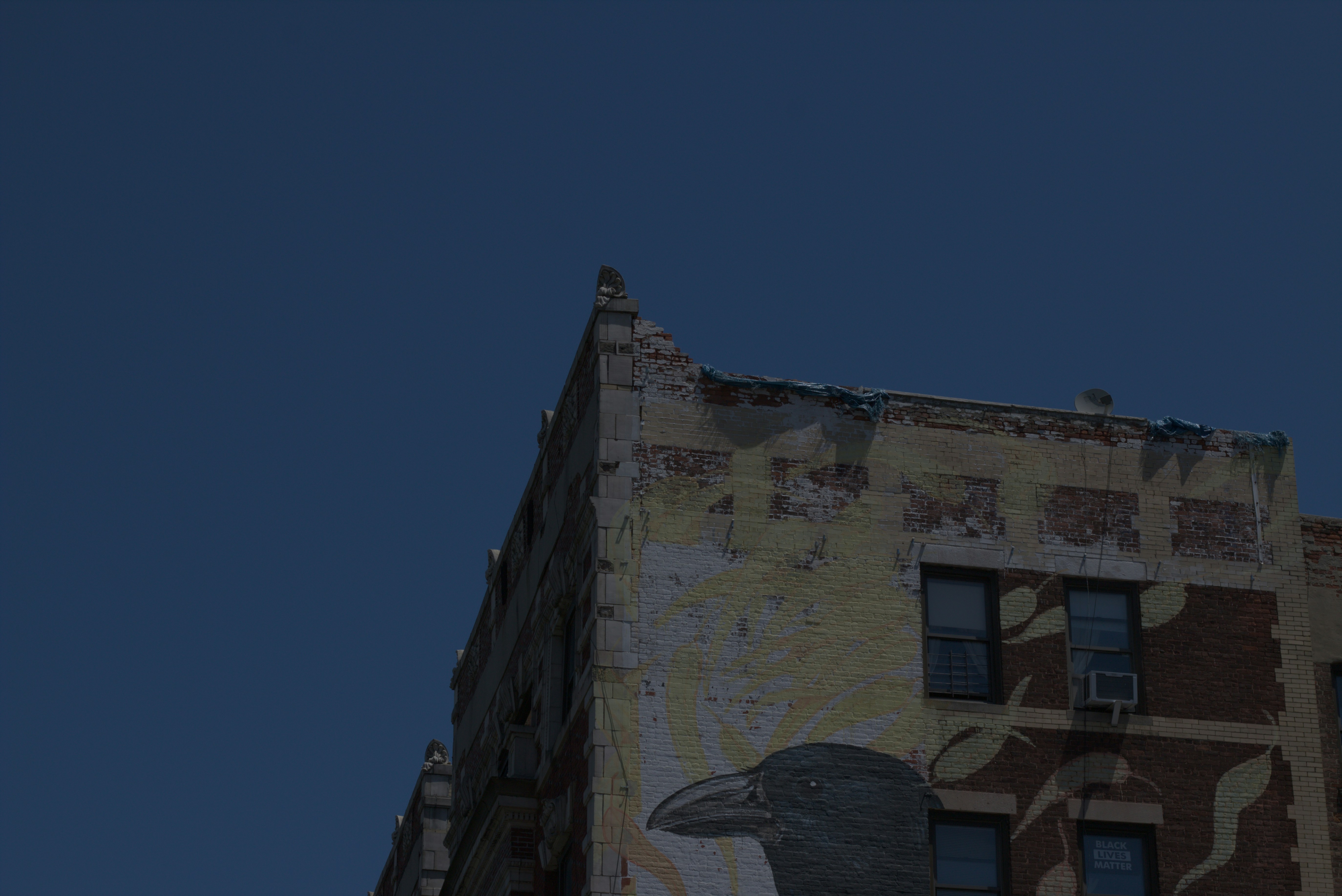 Sunlit Corner Facade: Faded mural and weathered brick