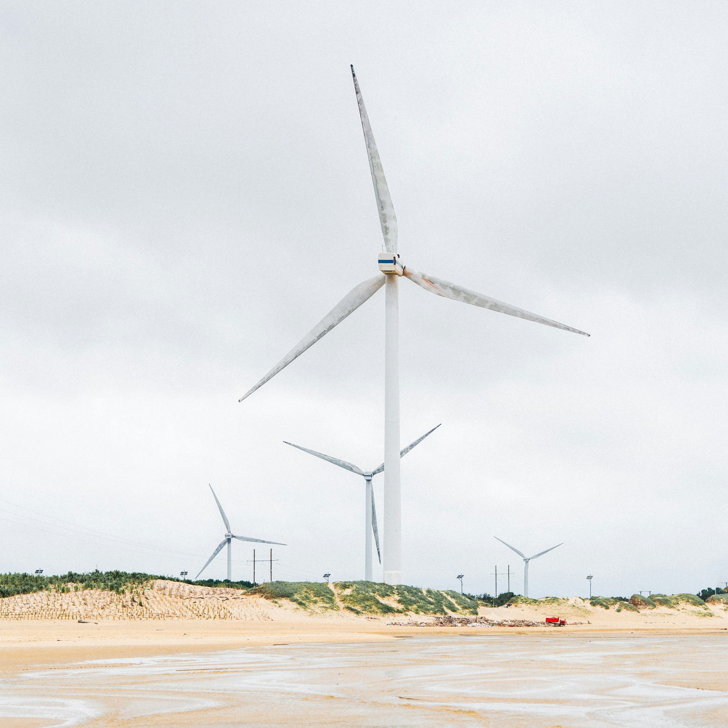 A group of wind turbines on a sandy beach photo – Free China Image on ...