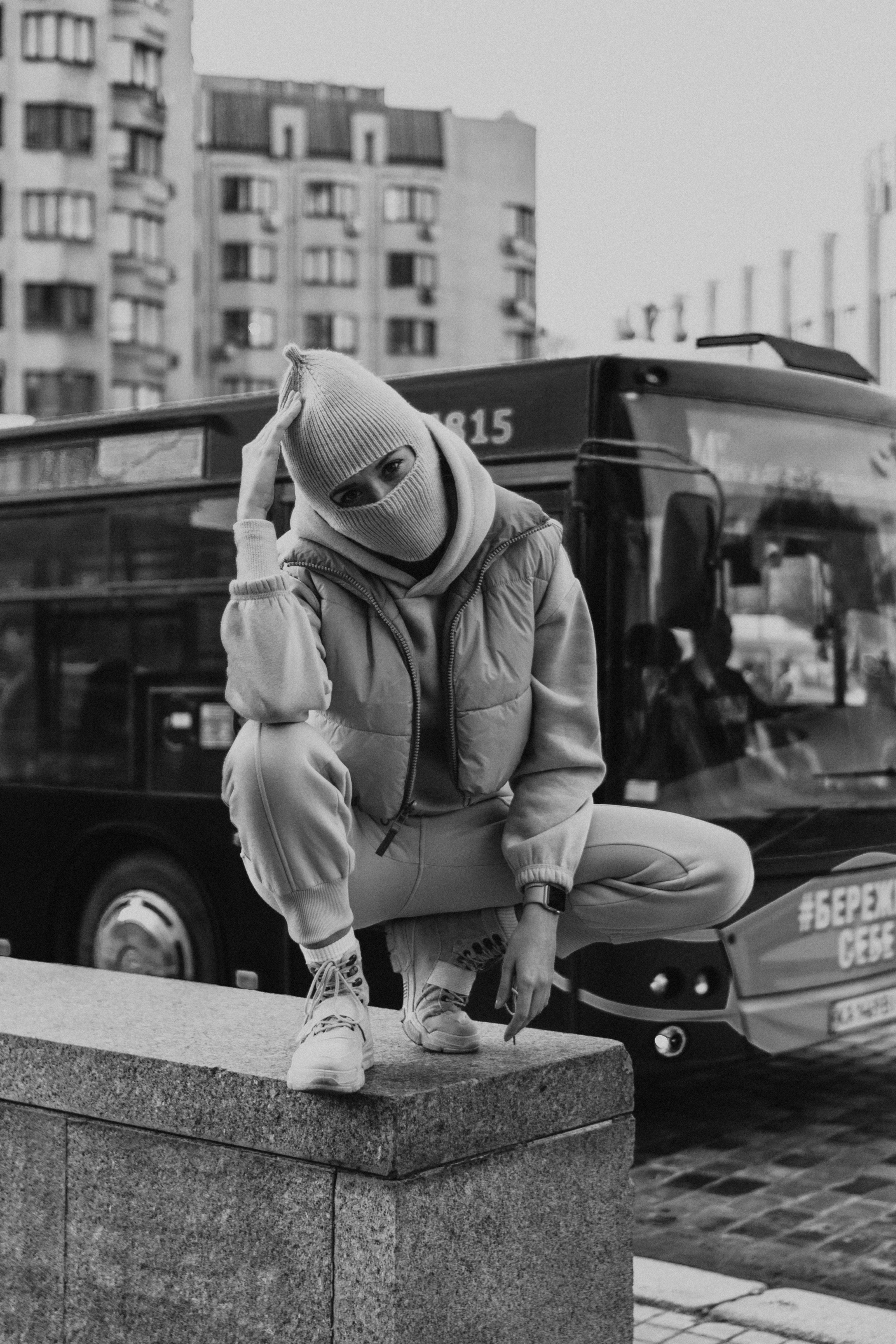 A person sitting on a ledge in front of a bus photo – Free Woman Image ...