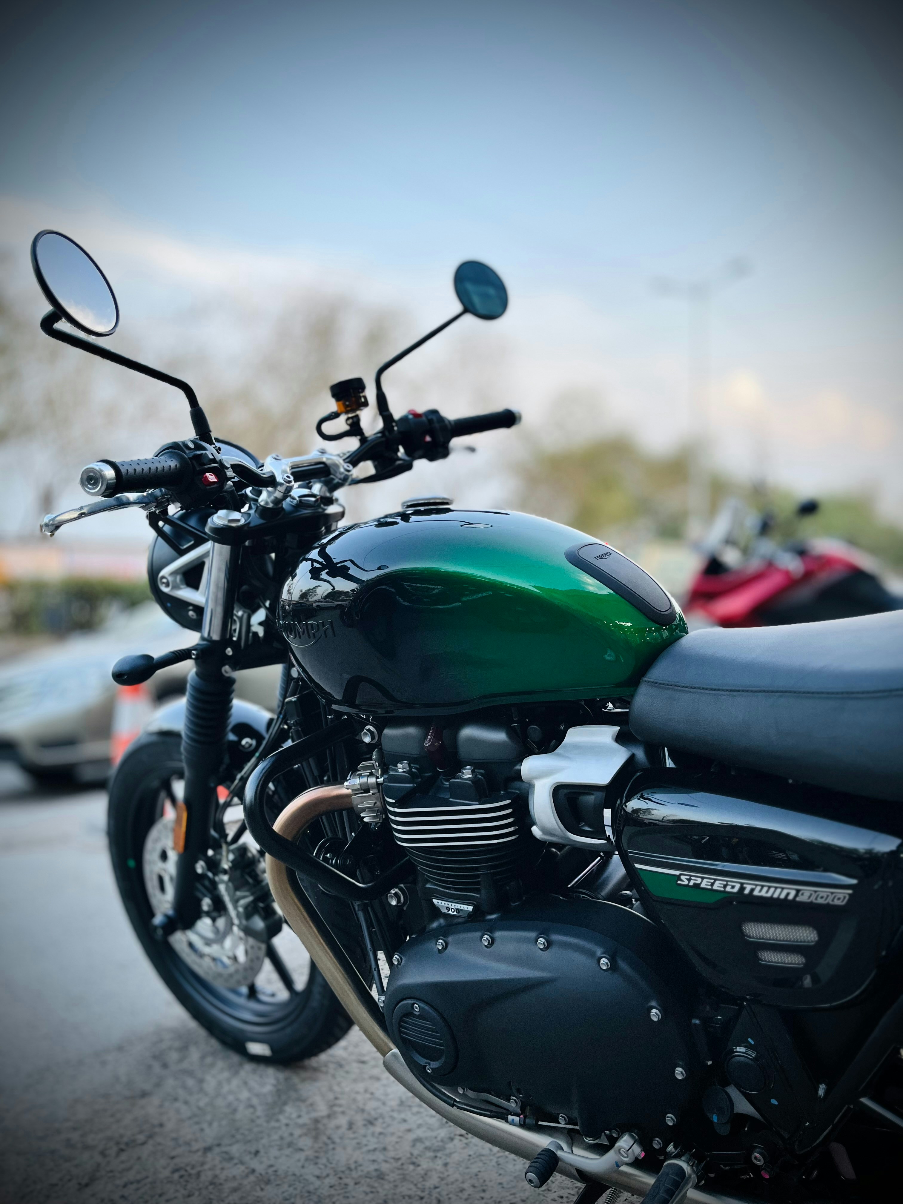Emerald Torque in Soft Daylight: Triumph Speed Twin Shines Against a Blurred Cityscape
