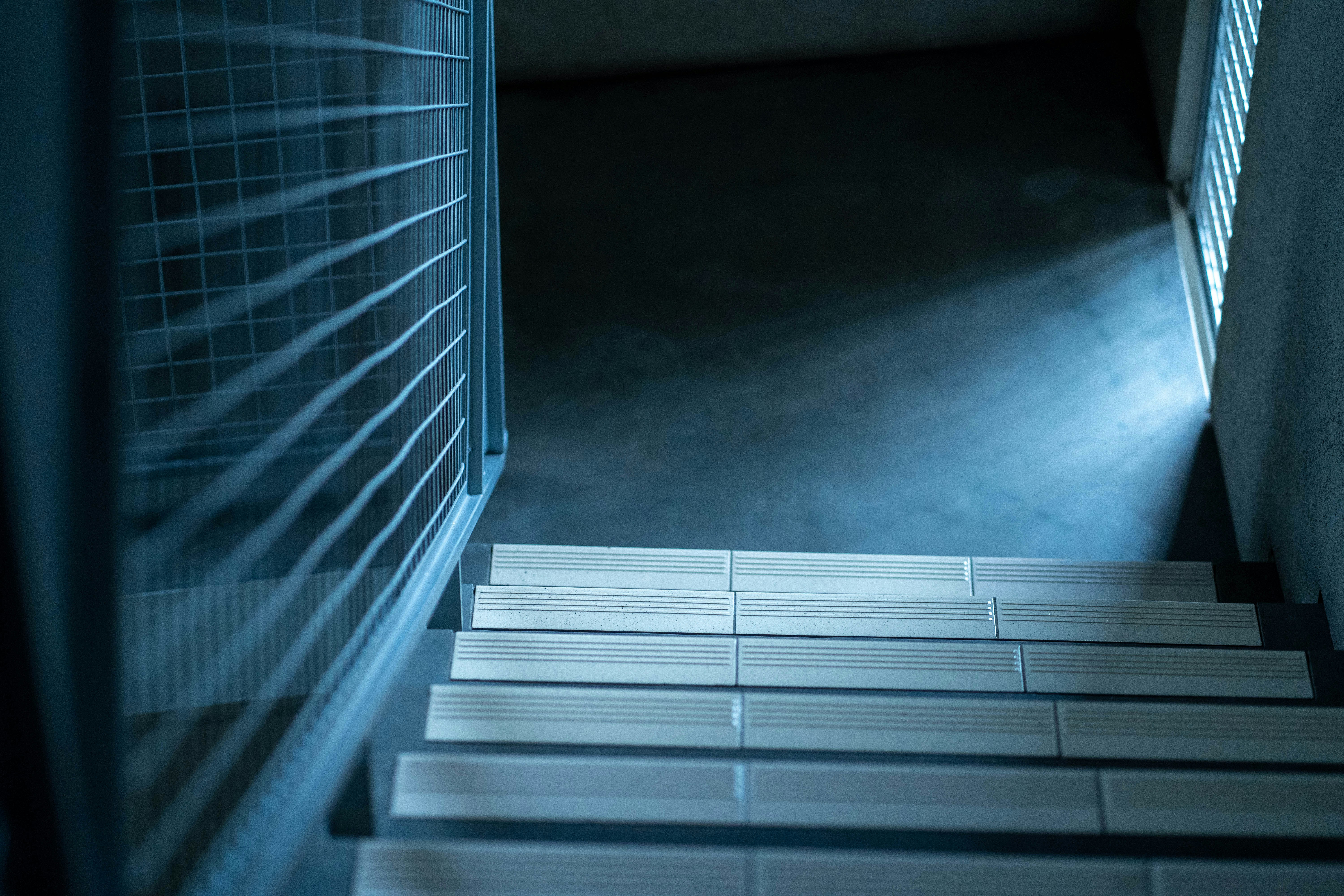 Blue Descent: An Industrial Staircase Vanishing into a Shadowed Hall