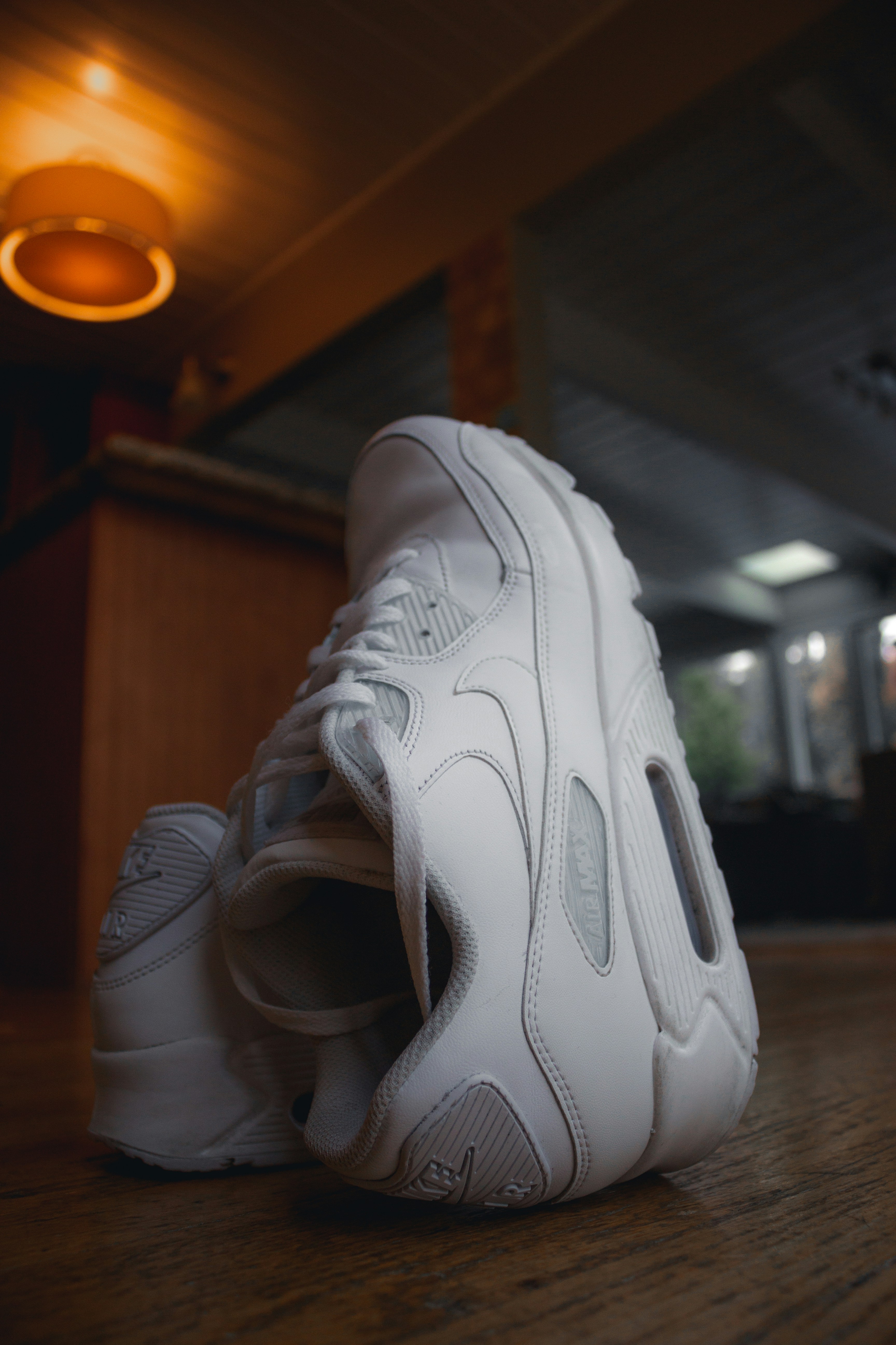 Amber Glow on White: A Sneaker's Quiet Moment on Wood