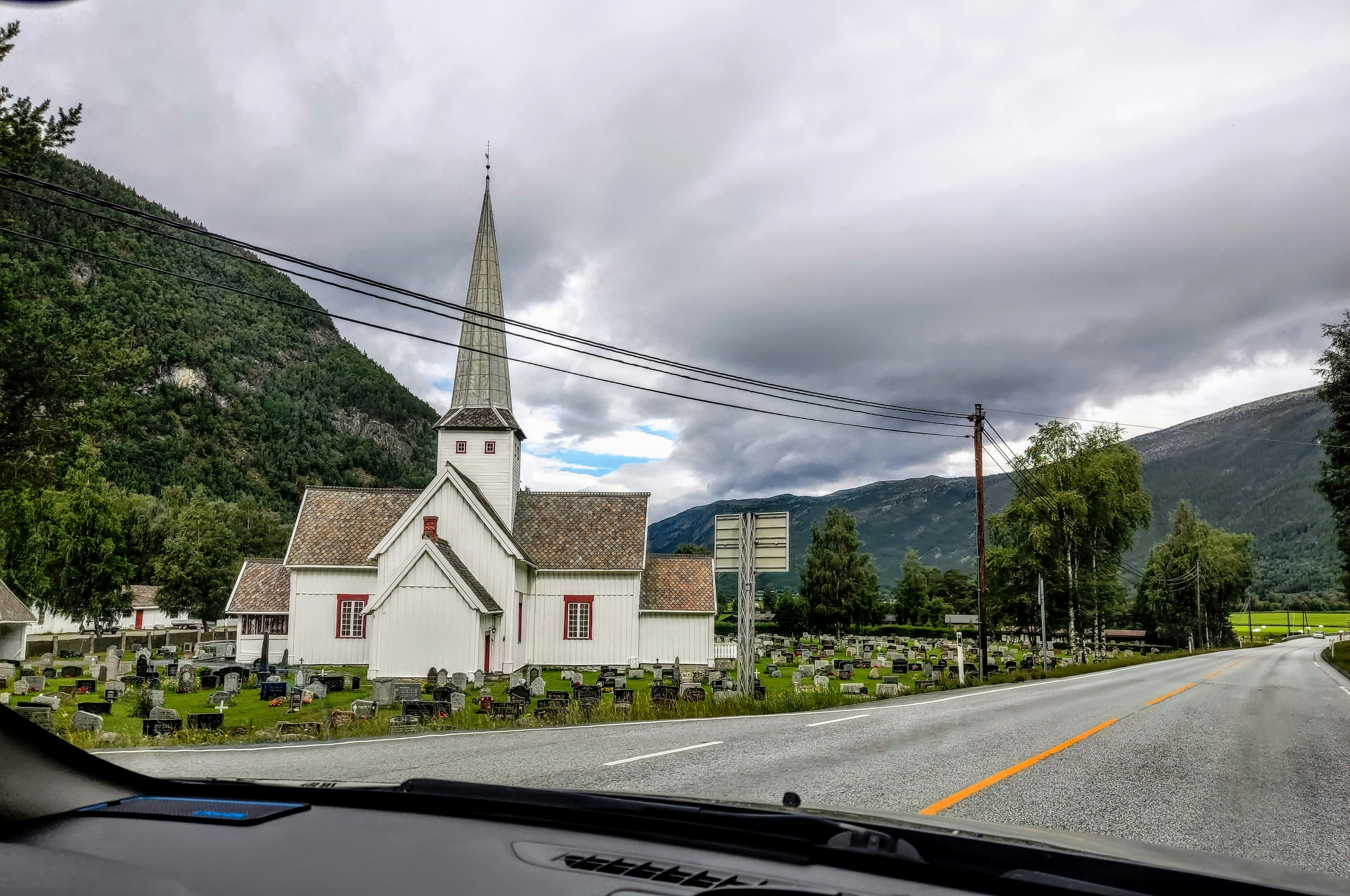 Steepled Sanctuary by a Mountain Road Under a Cloudy Sky