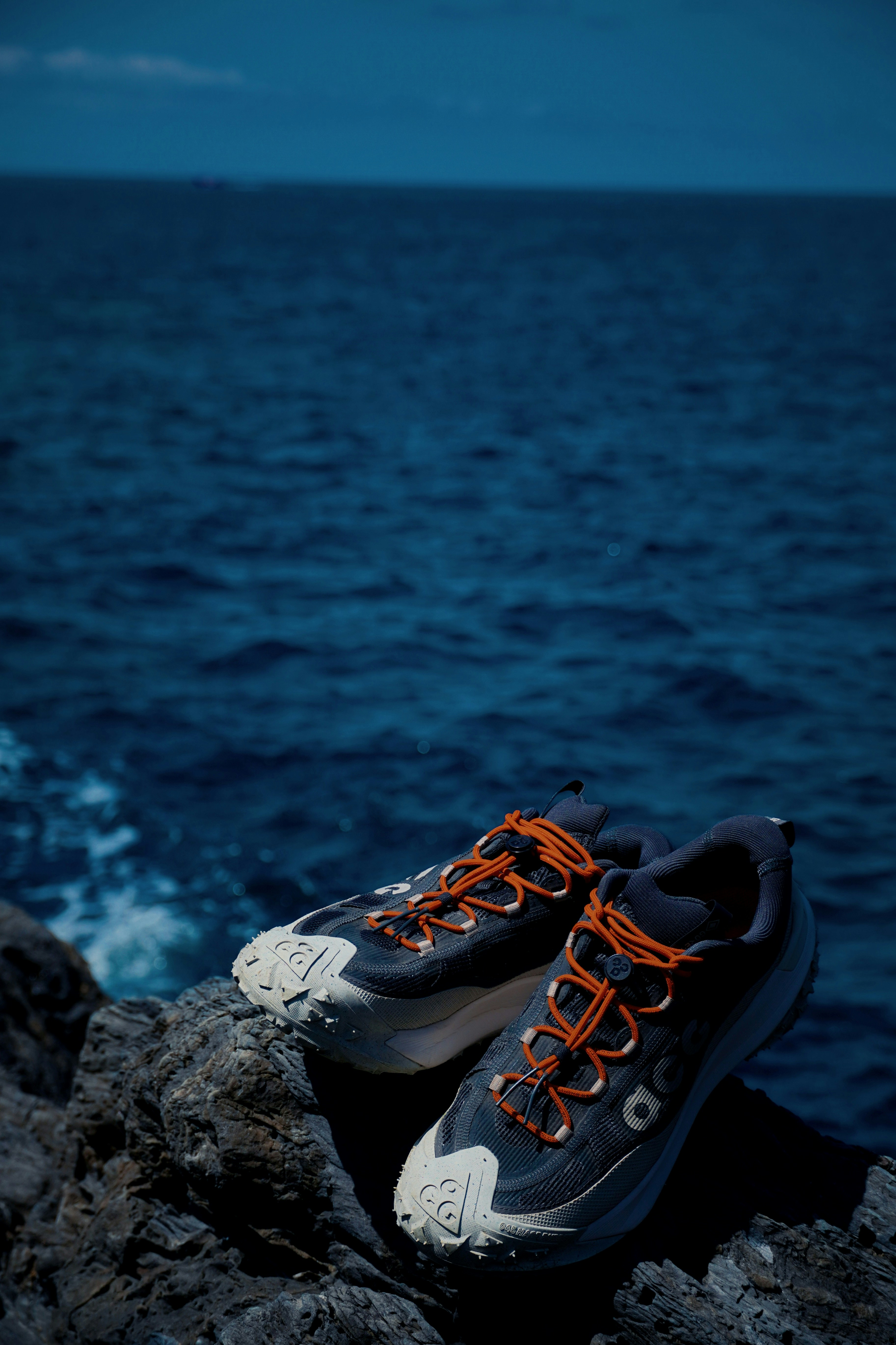 Orange-Laced Trail Shoes Perched on Rugged Sea Rocks