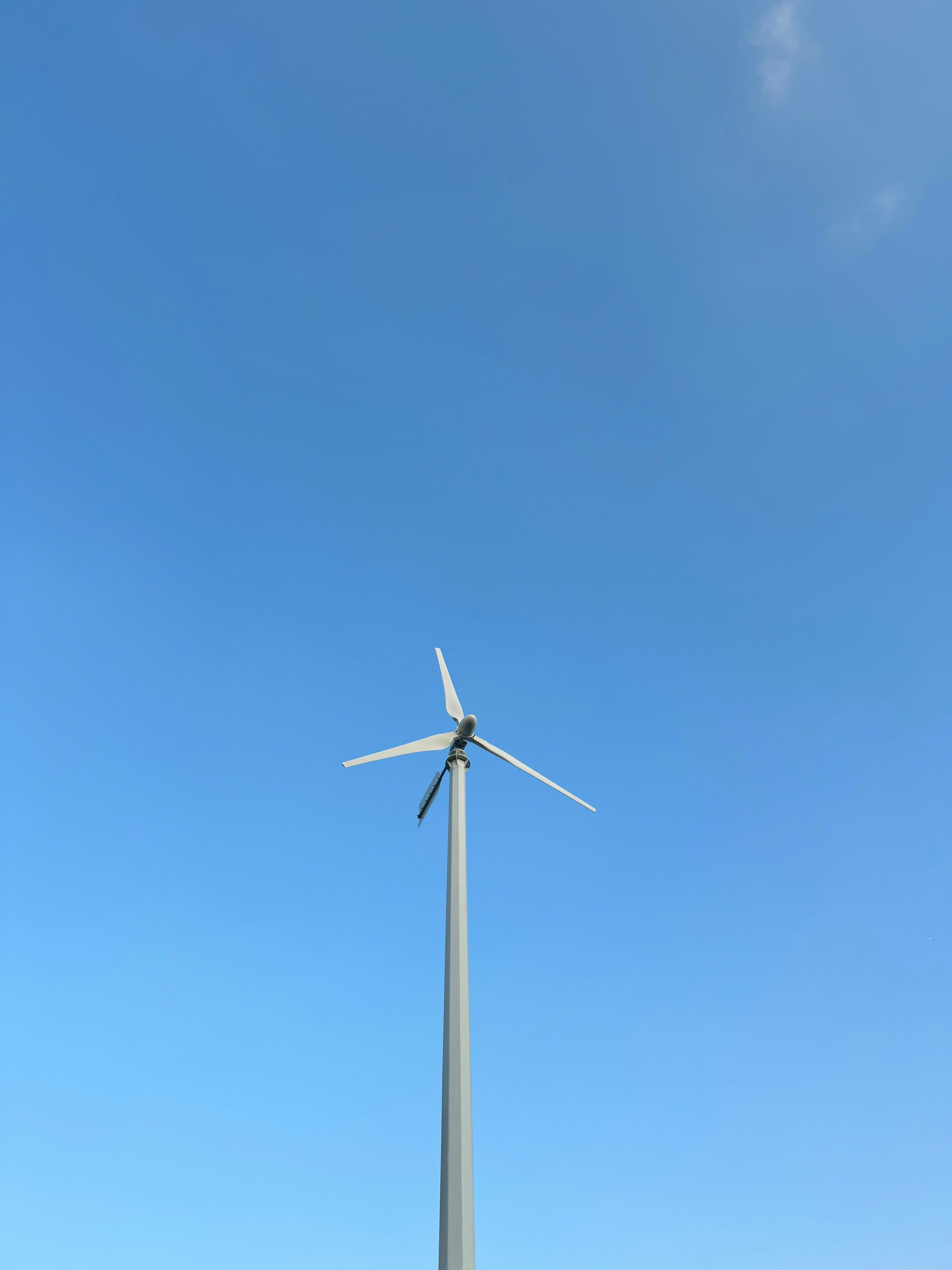 A Lone Wind Turbine Silhouette Against a Powder-Blue Sky