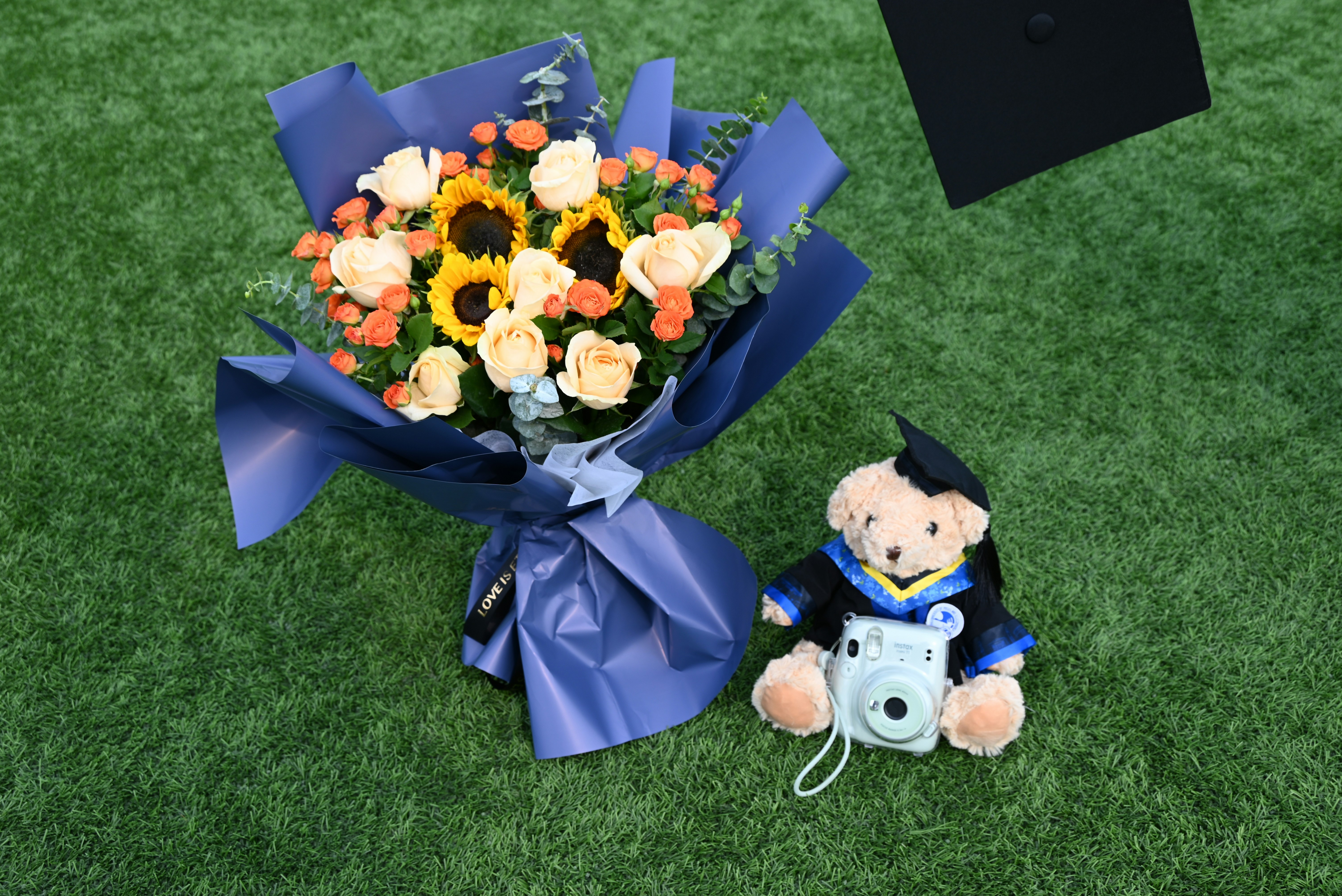 A graduation cap and a teddy bear with a bouquet of flowers photo ...