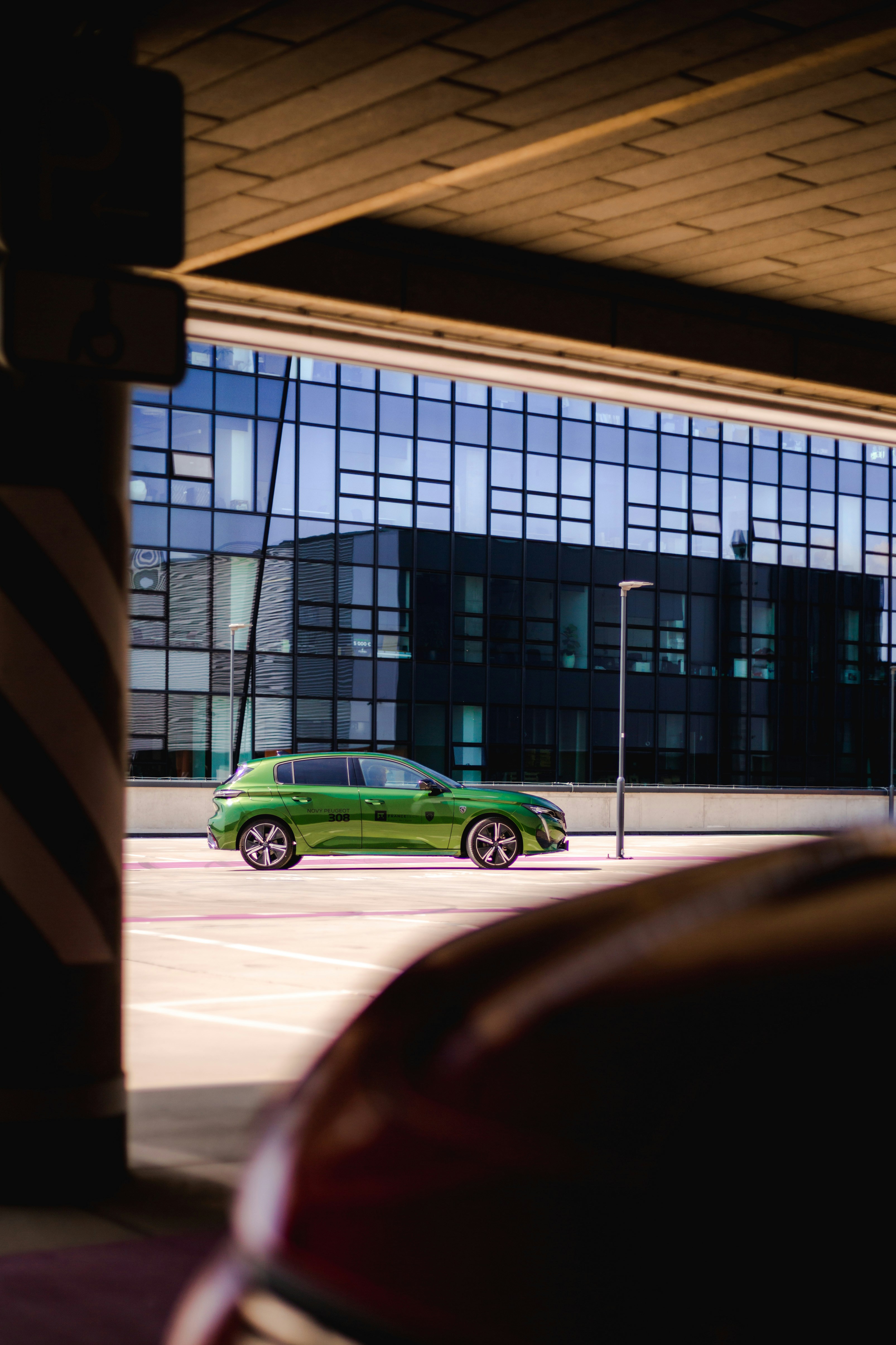 Emerald Hatchback Under a Geometric Glass Canopy