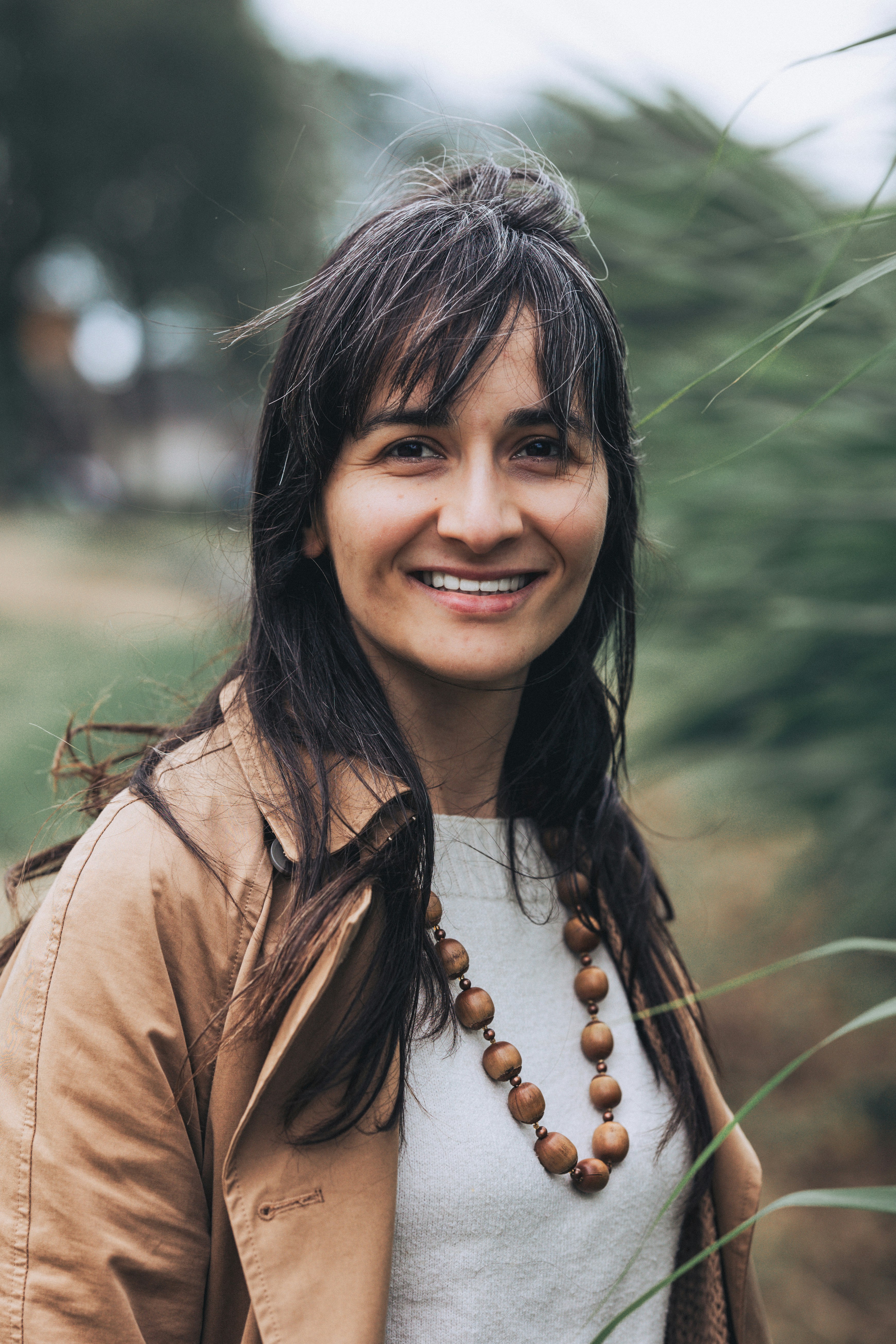 Portrait in the Wind: Warm Smile Among Soft Greens