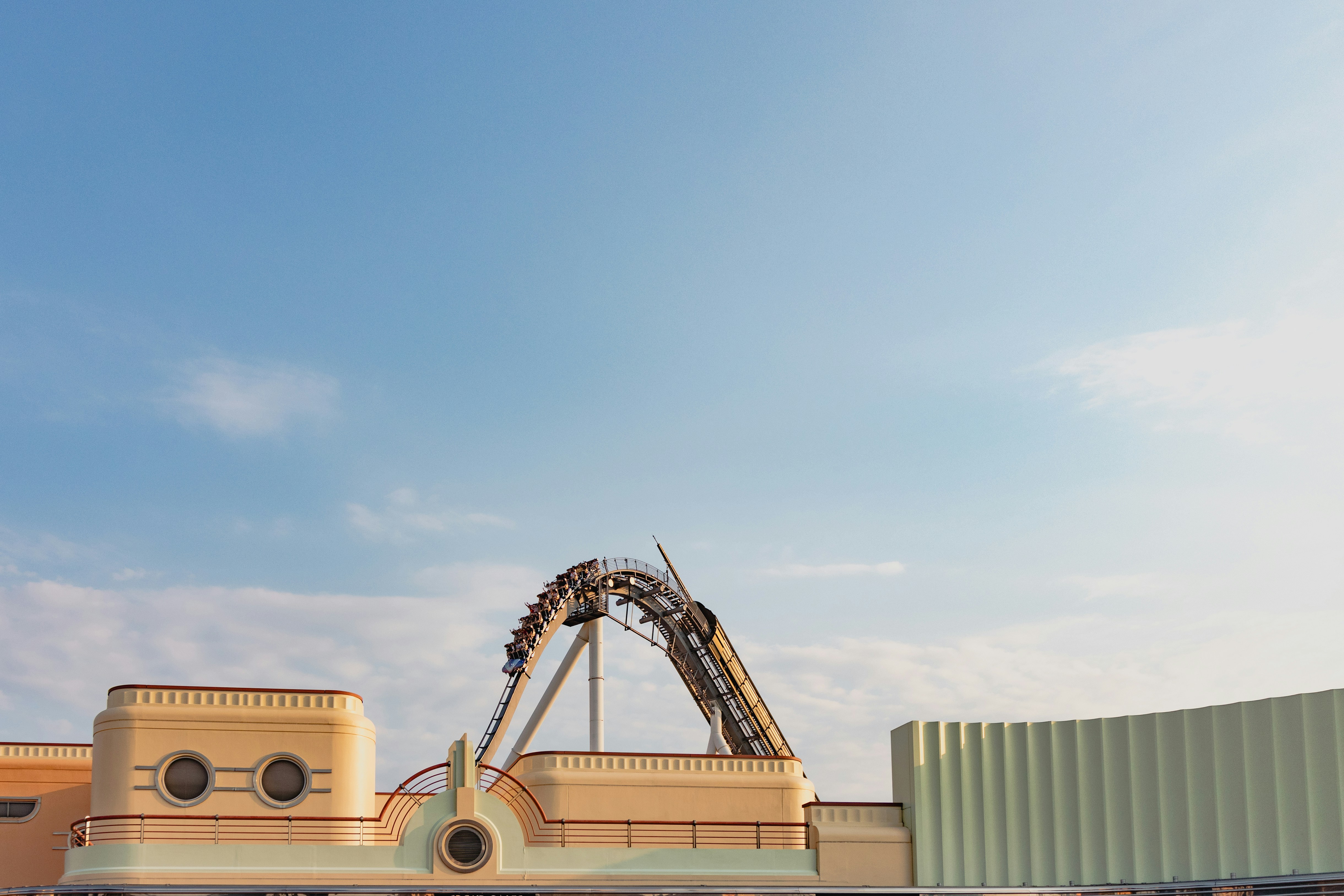 Arching Roller Coaster Silhouette Over Art-Deco Roofline