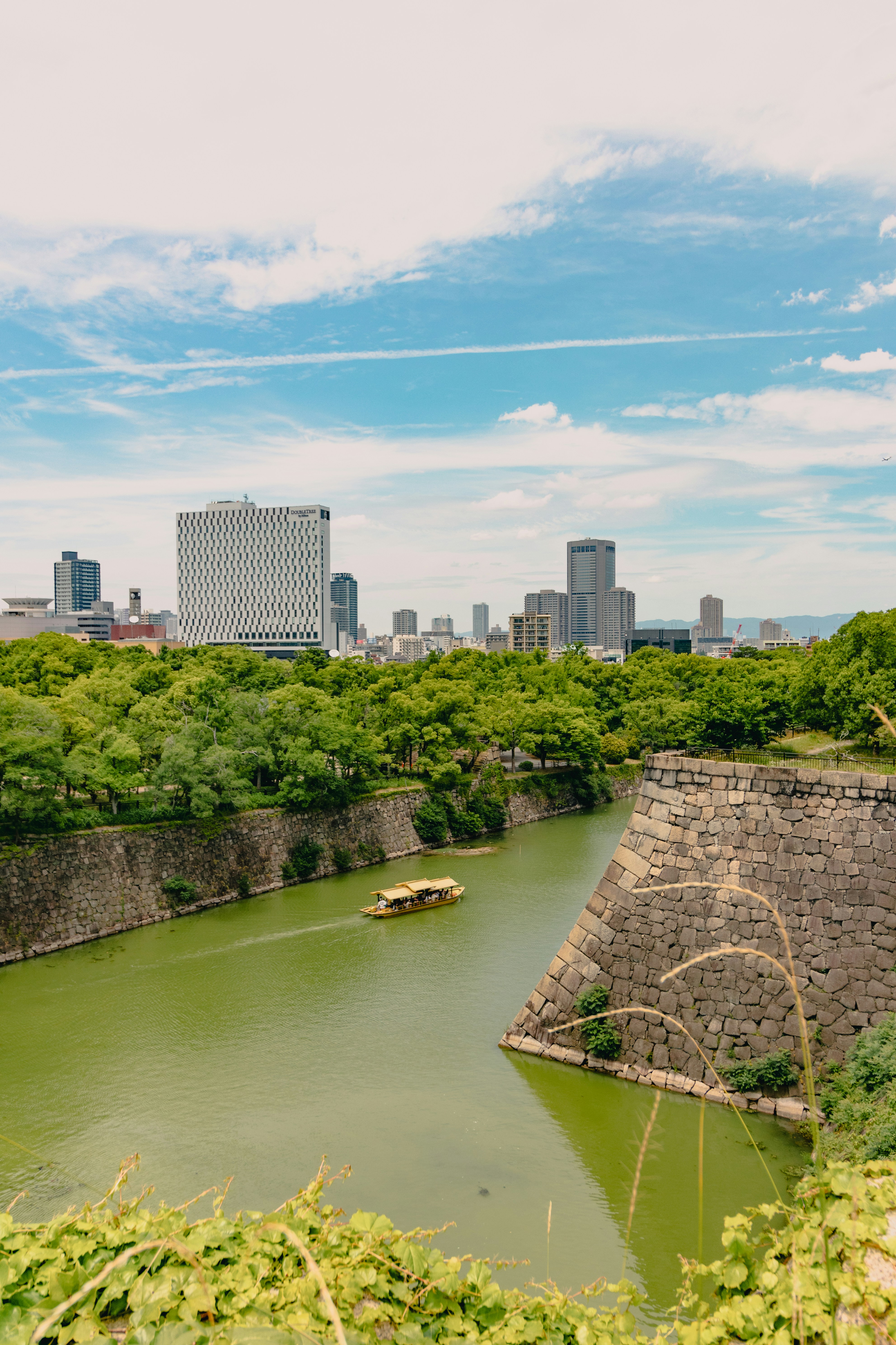 Riverside Voyage: A Small Boat Traces the Green Canal Under a Modern Skyline