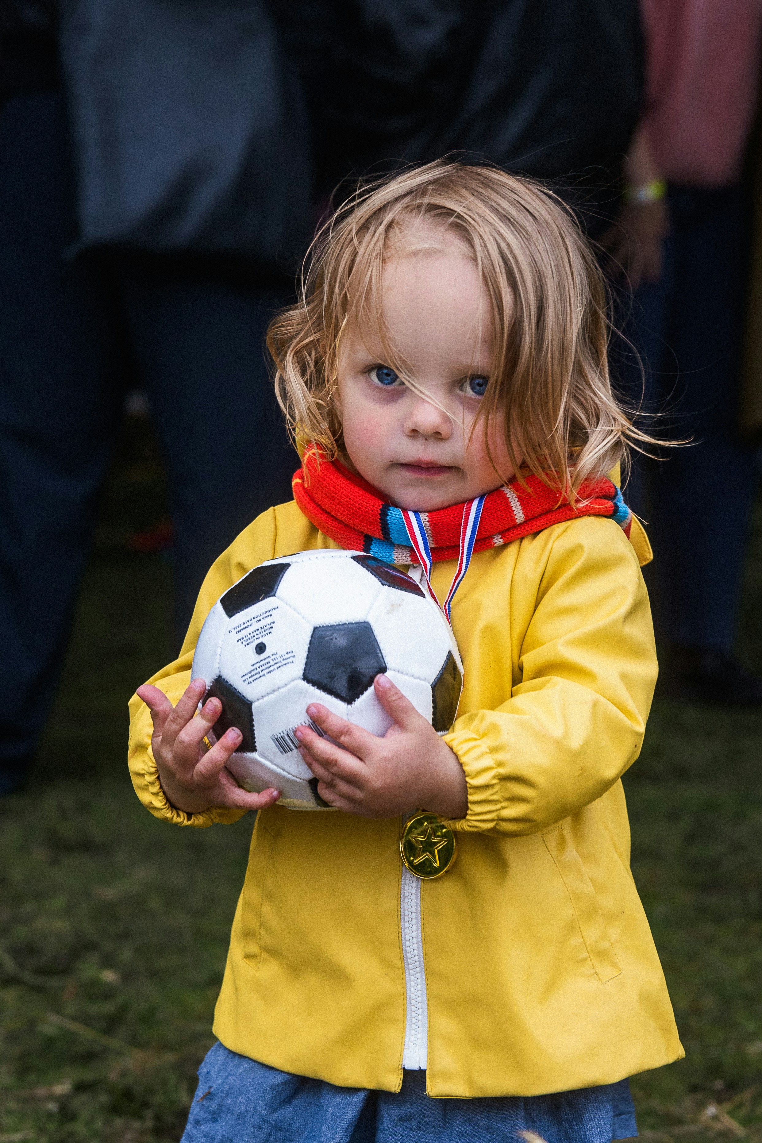 Brave Little Keeper in Yellow: Medal Moment with a Soccer Ball