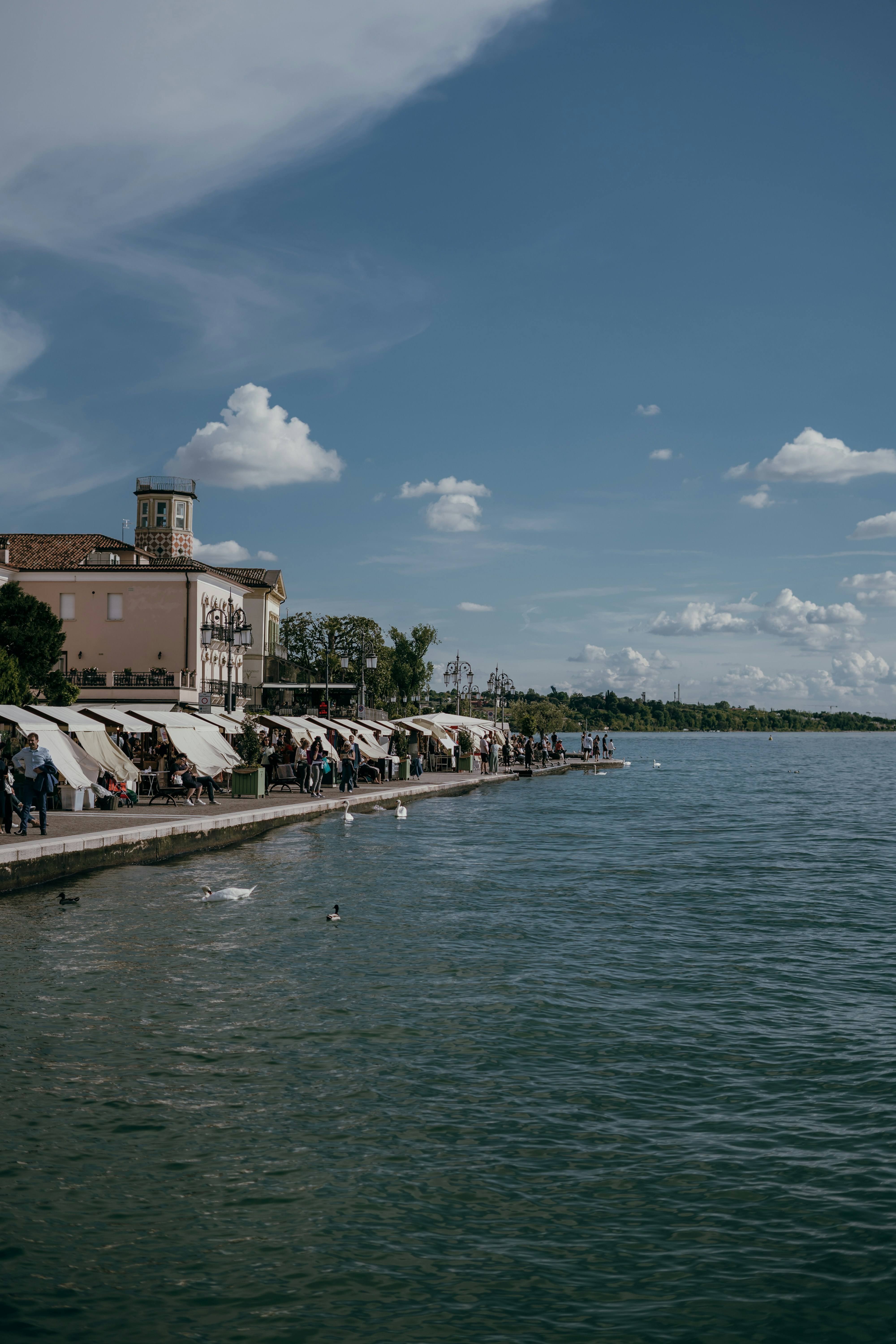 Quayside Quiet: Sunlit cafés and a distant clocktower along the lakeside promenade