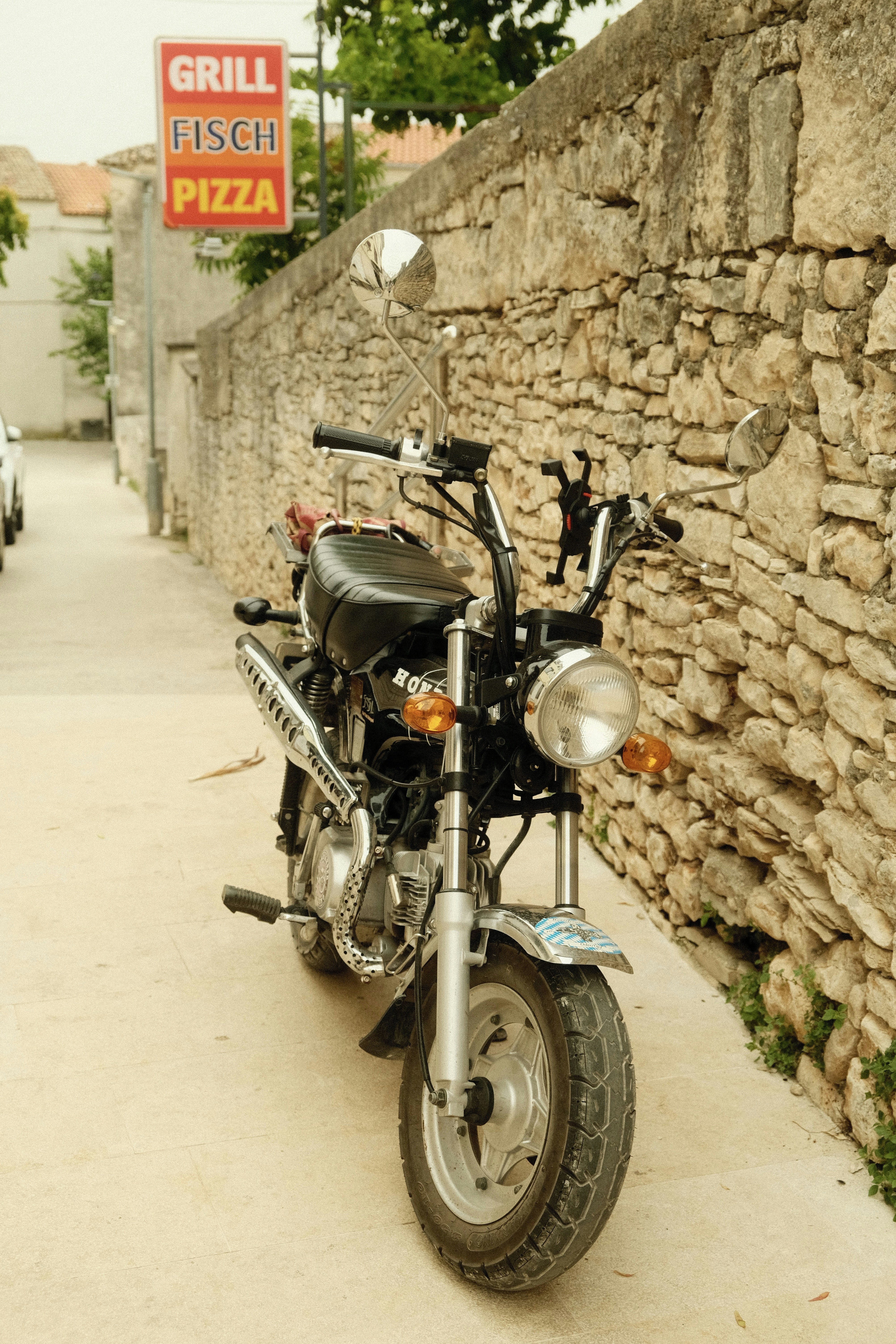 Alley Torque: A Vintage Motorcycle Paused Beside a Weathered Stone Wall