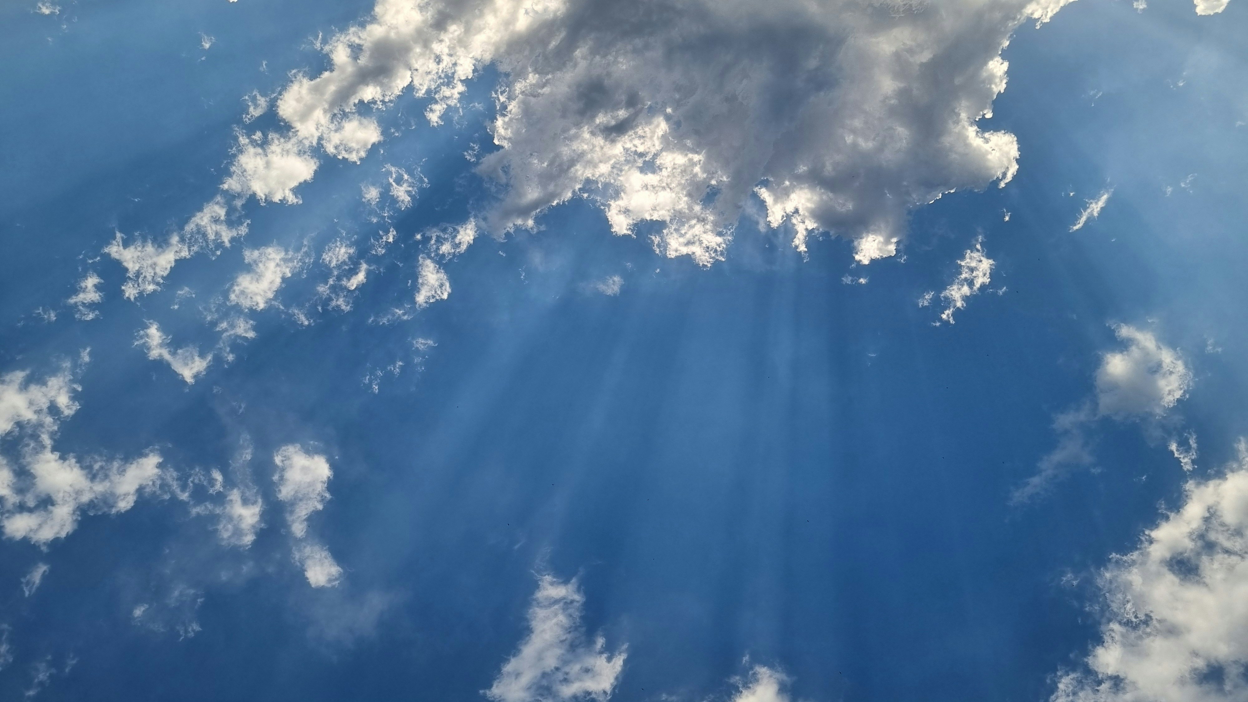 The sun is shining through the clouds in the sky