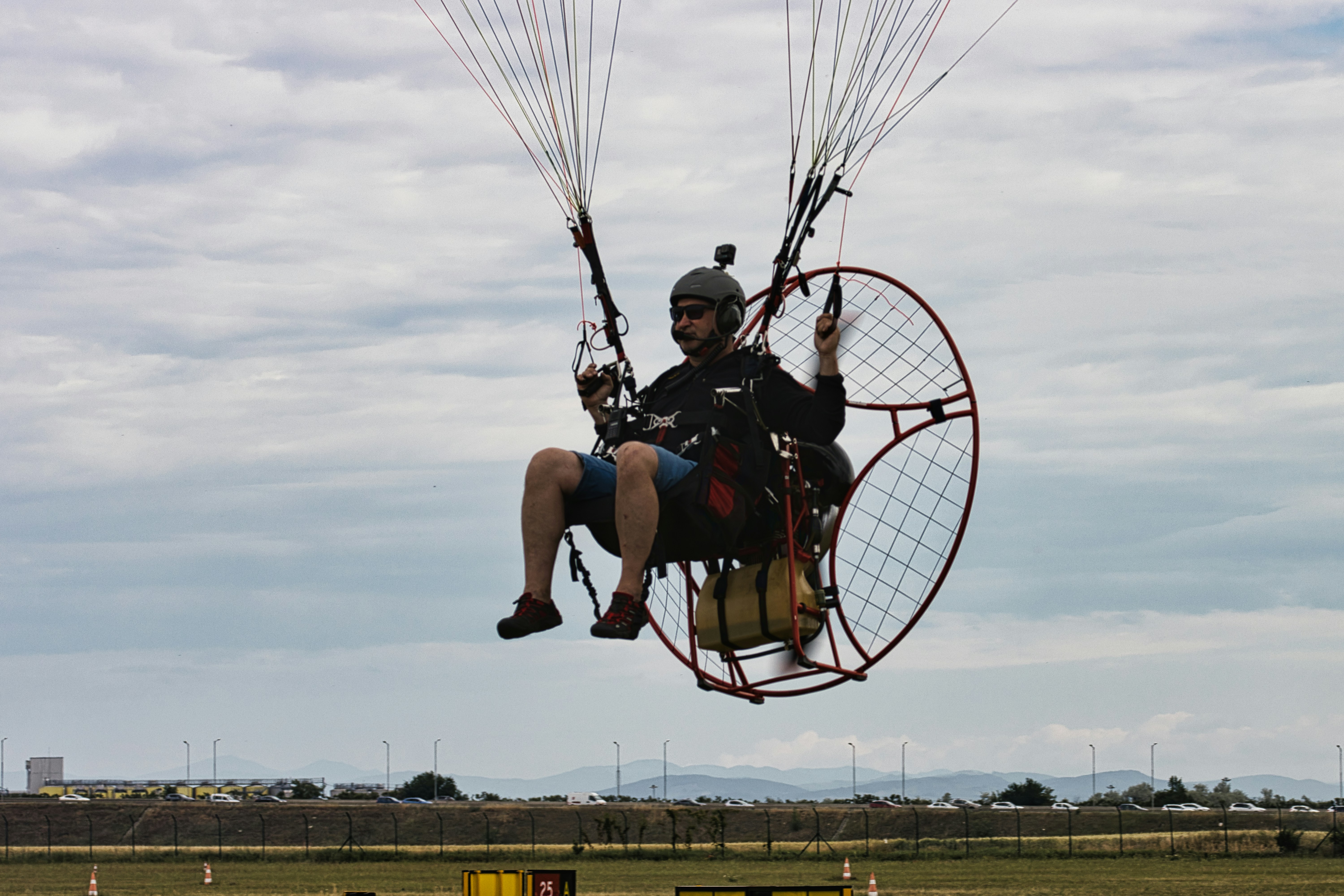 Hovering Pilot: A Solo Paraglider Suspended Above a Tarmac Panorama