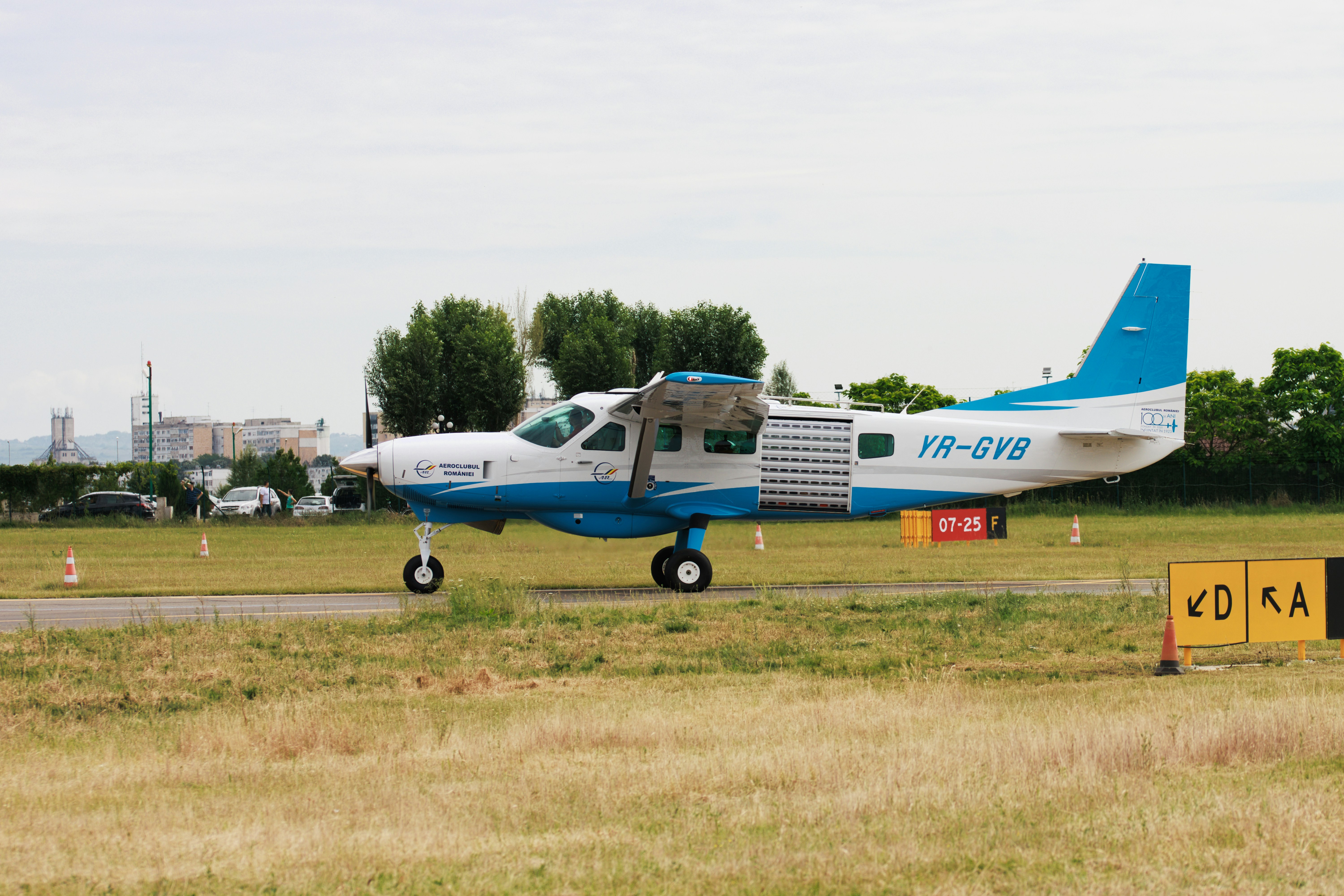 Blue-Trim Light Aircraft Taxis Across a Sunlit Grass Airfield