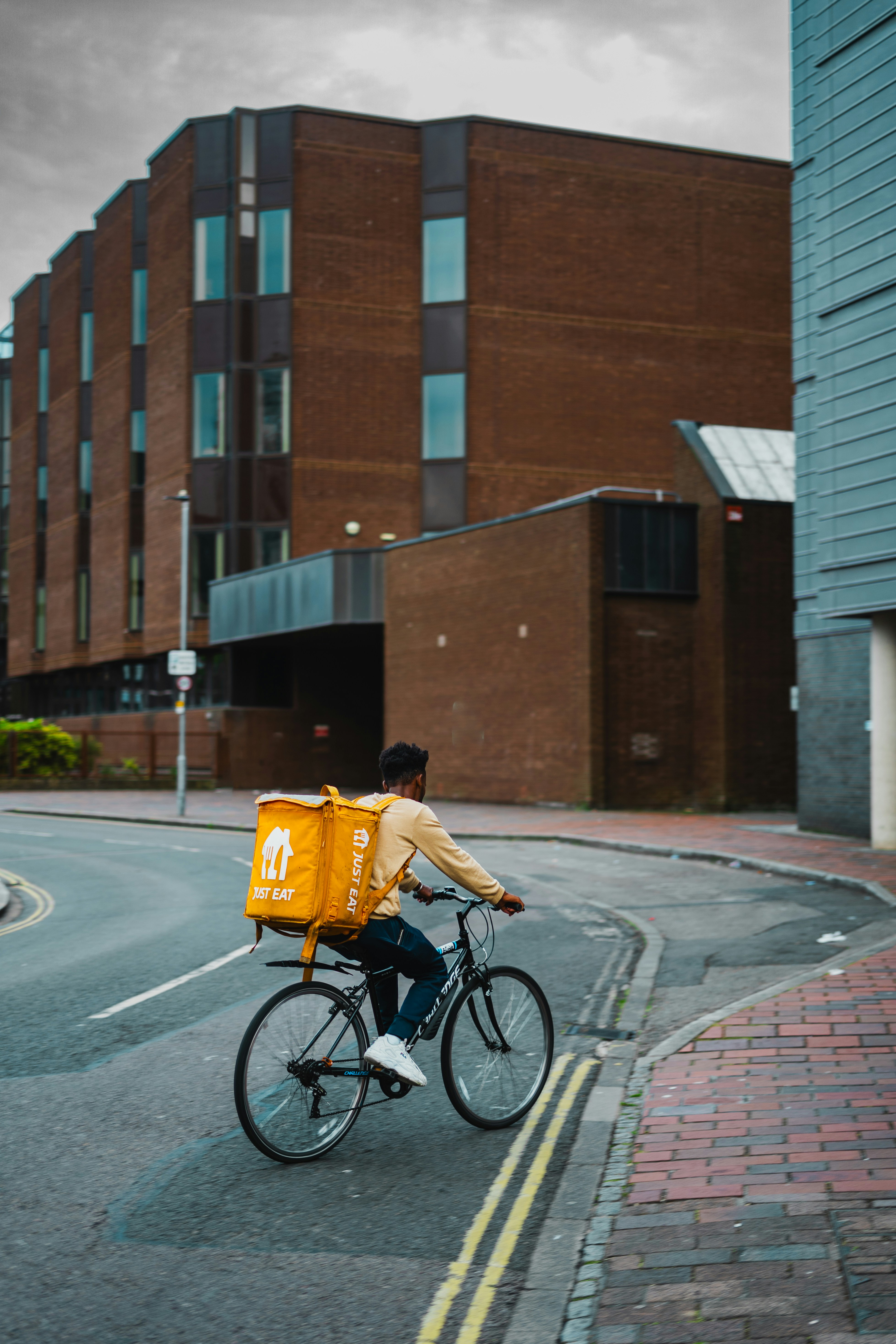 Orange-Backpack Courier Navigates a Brick-City Bend