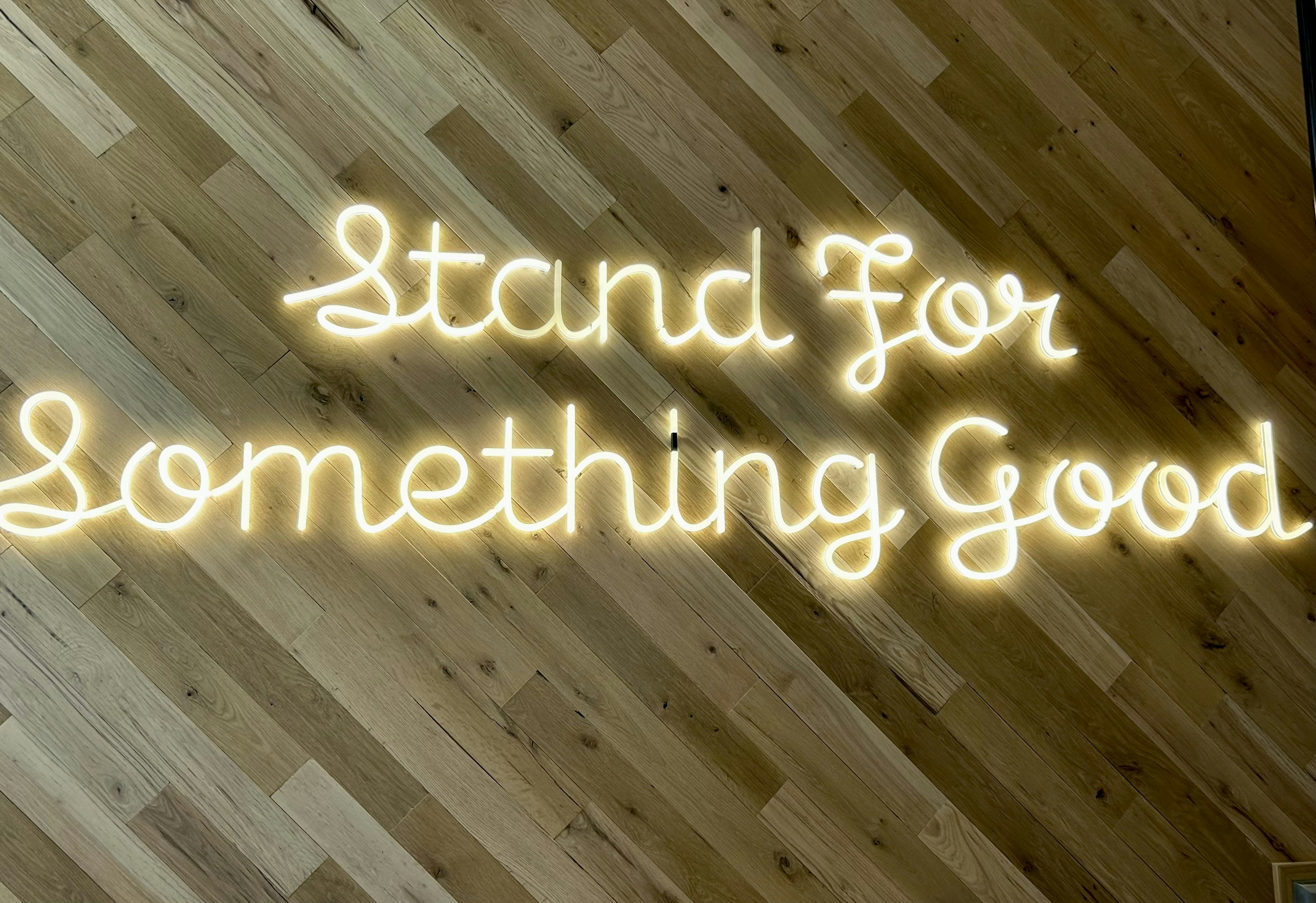 A wooden floor with a neon sign that says stand for something good ...