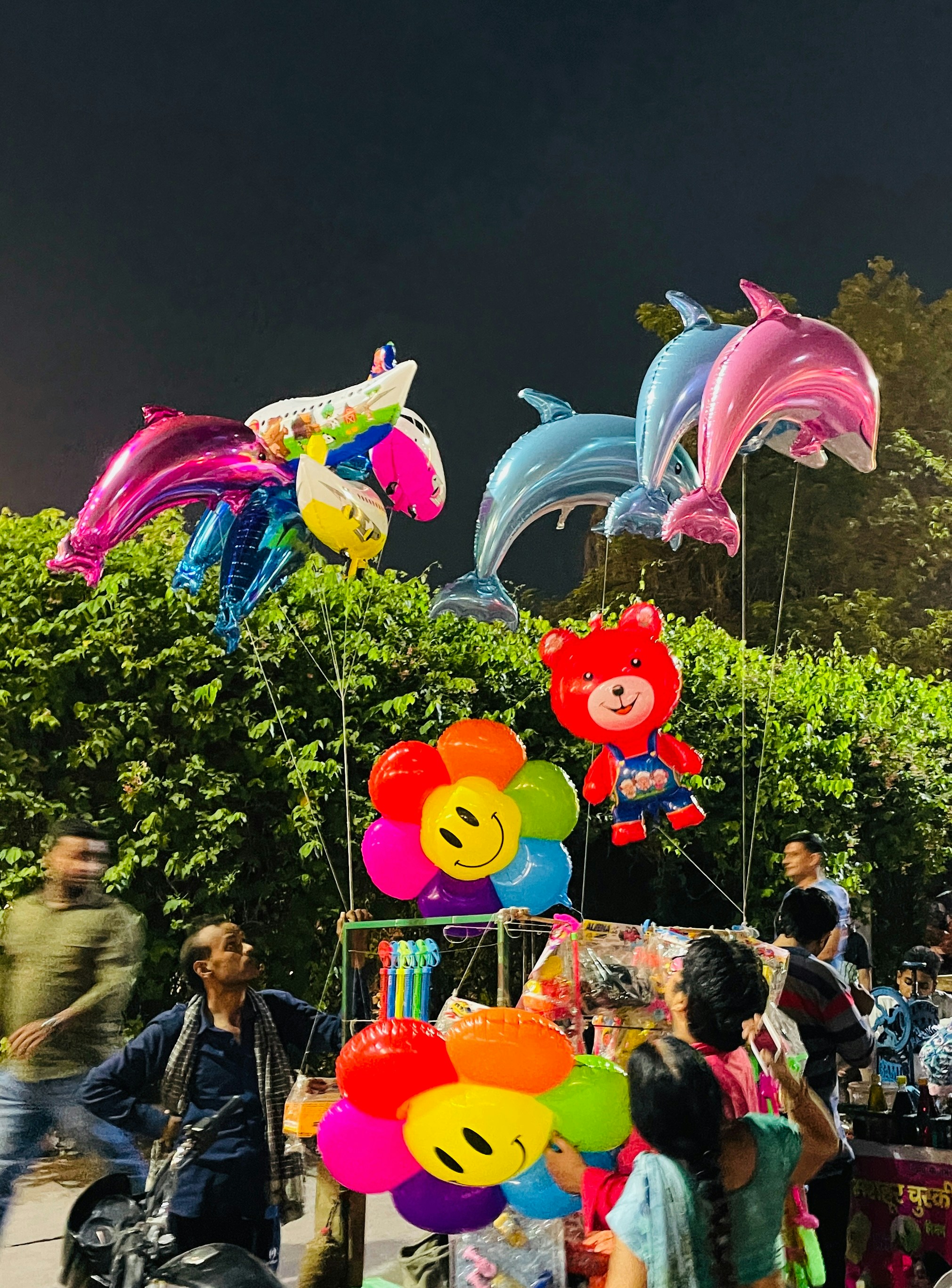 Red Bear Above the Neon Market: A Night-Bloom of Balloons Over a Bustling Stall