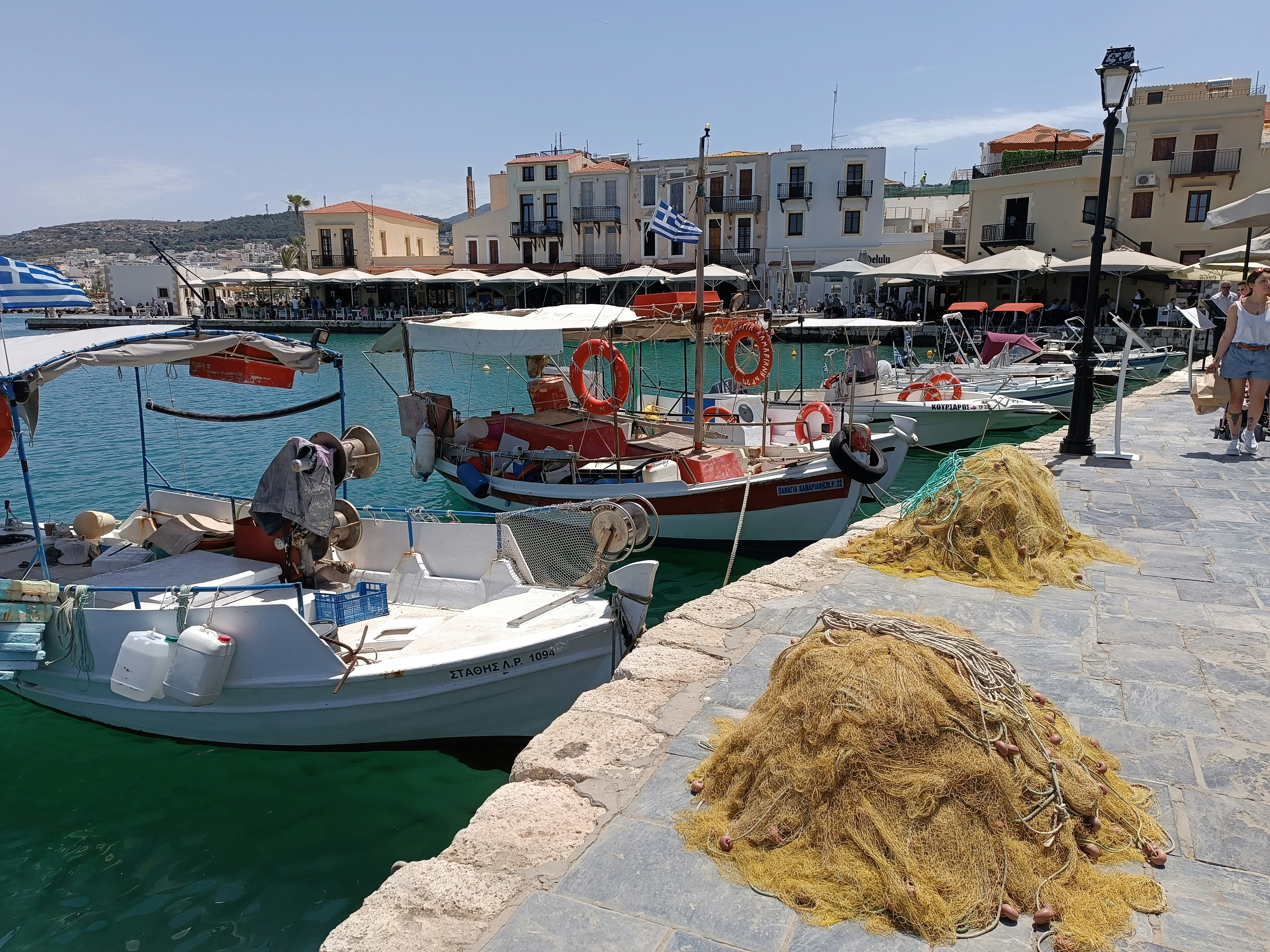 Fishing boats anchored at a vibrant harbor, surrounded by cafes and fishing nets. The scene captures the essence of coastal living.