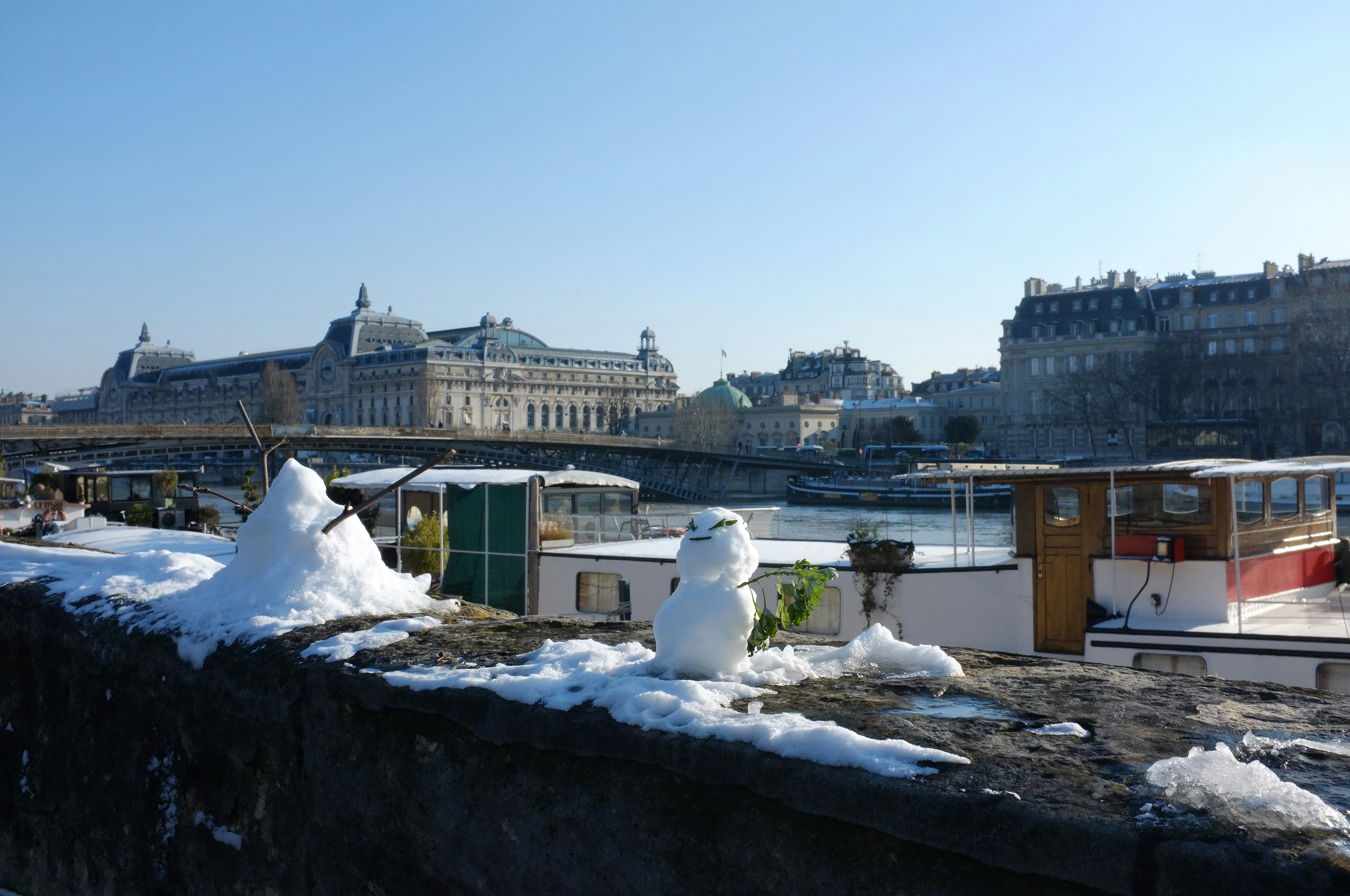 Snowlit Parisian Quay: Twin Snow Figures Guard the Riverfront