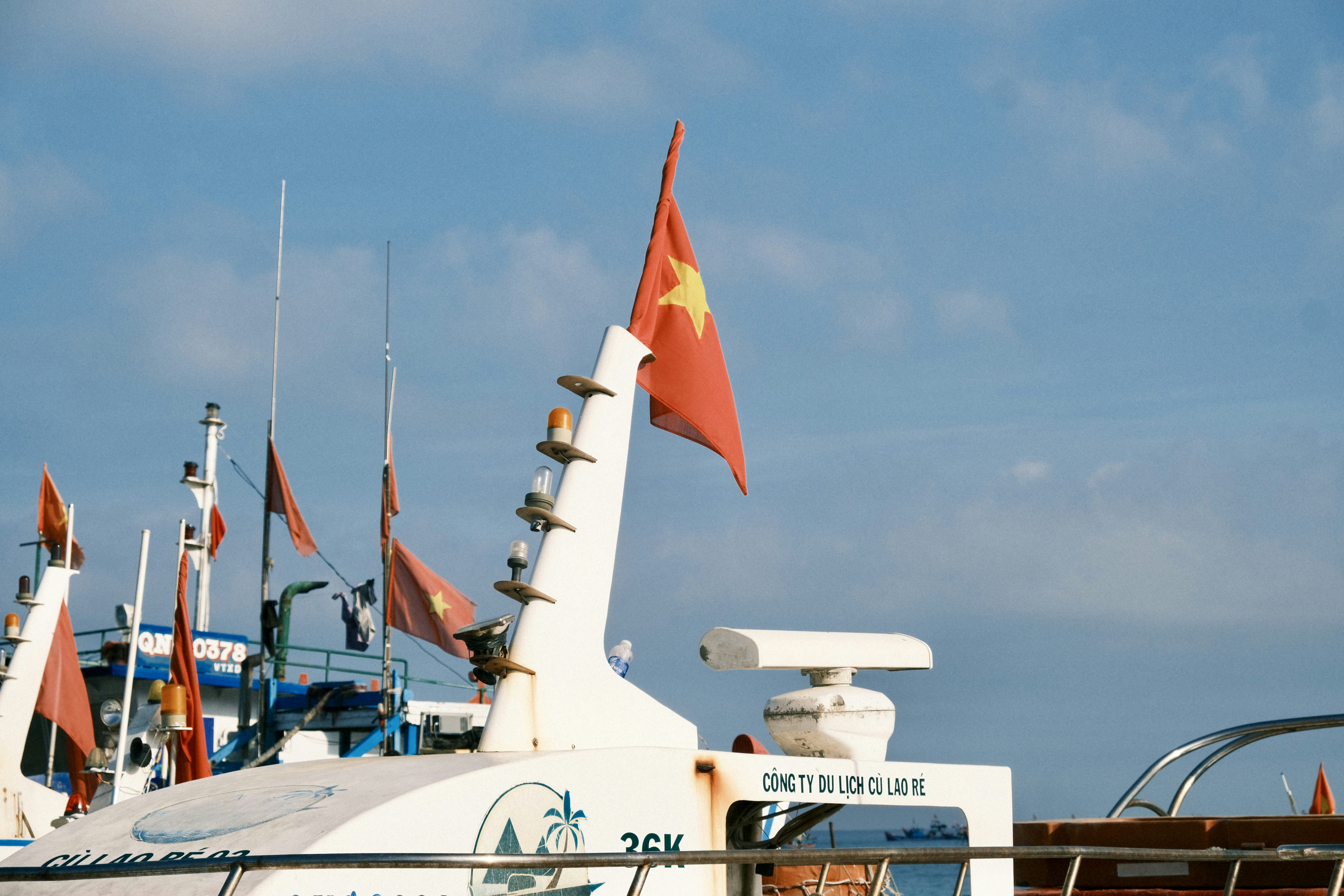 Crimson Flag Rising Over a Harbor Vessel's White Mast