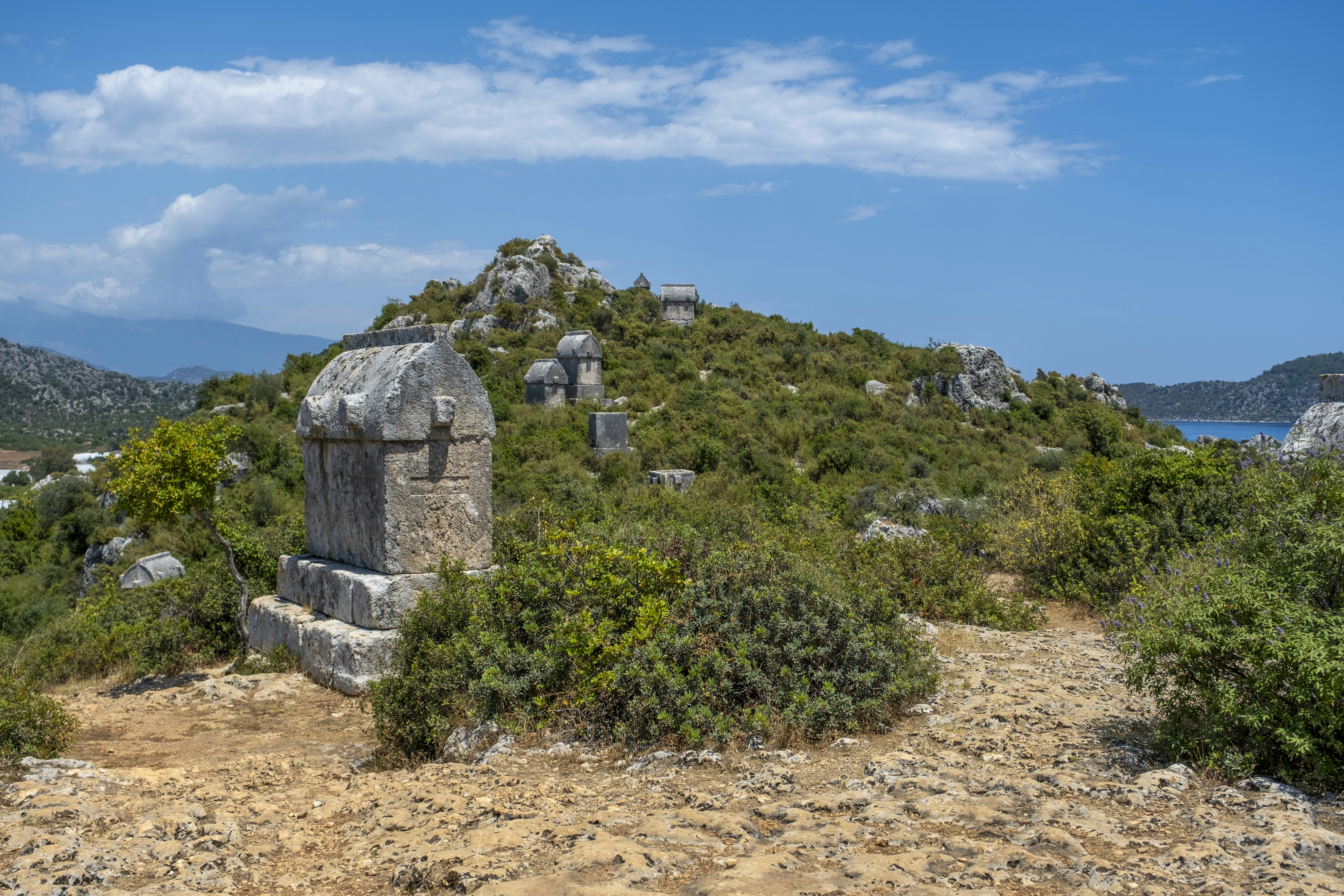 Ancient stone monument atop sunlit scrubland hill