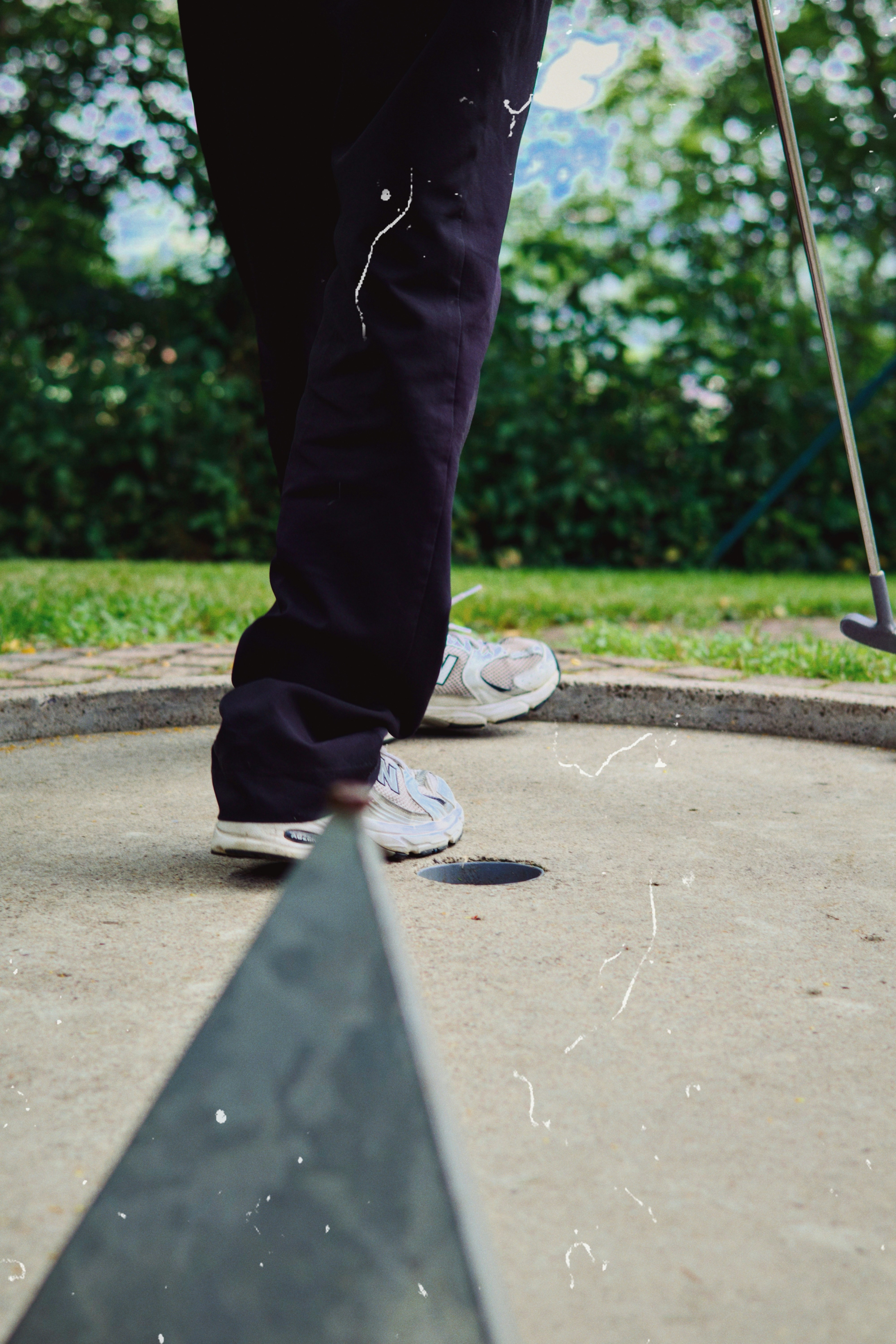 Grounded Focus: White Sneakers at the Golf Practice Mat