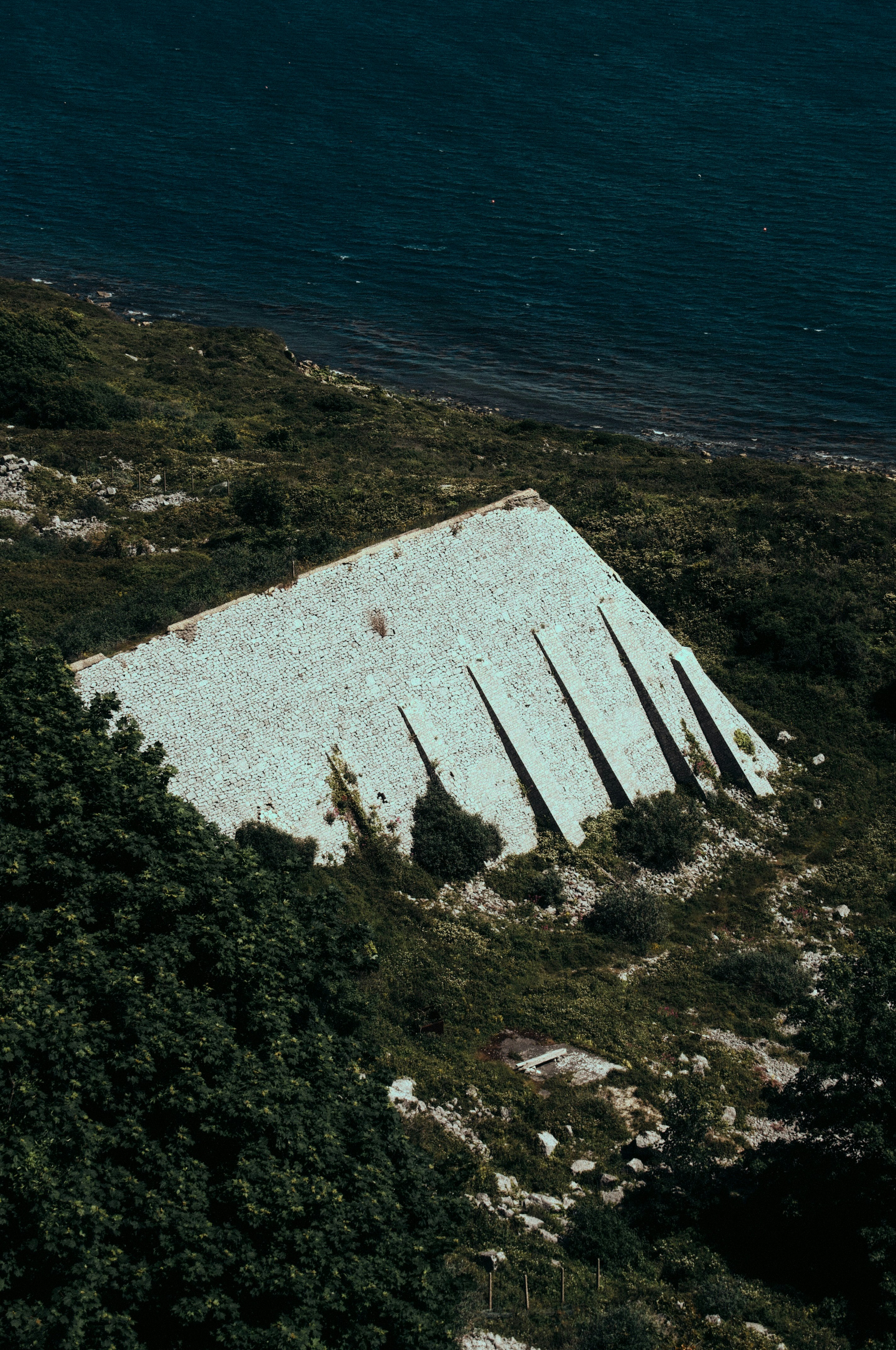 Leaning Concrete Slab: A Weathered Relic Guarding the Cliffside Shore