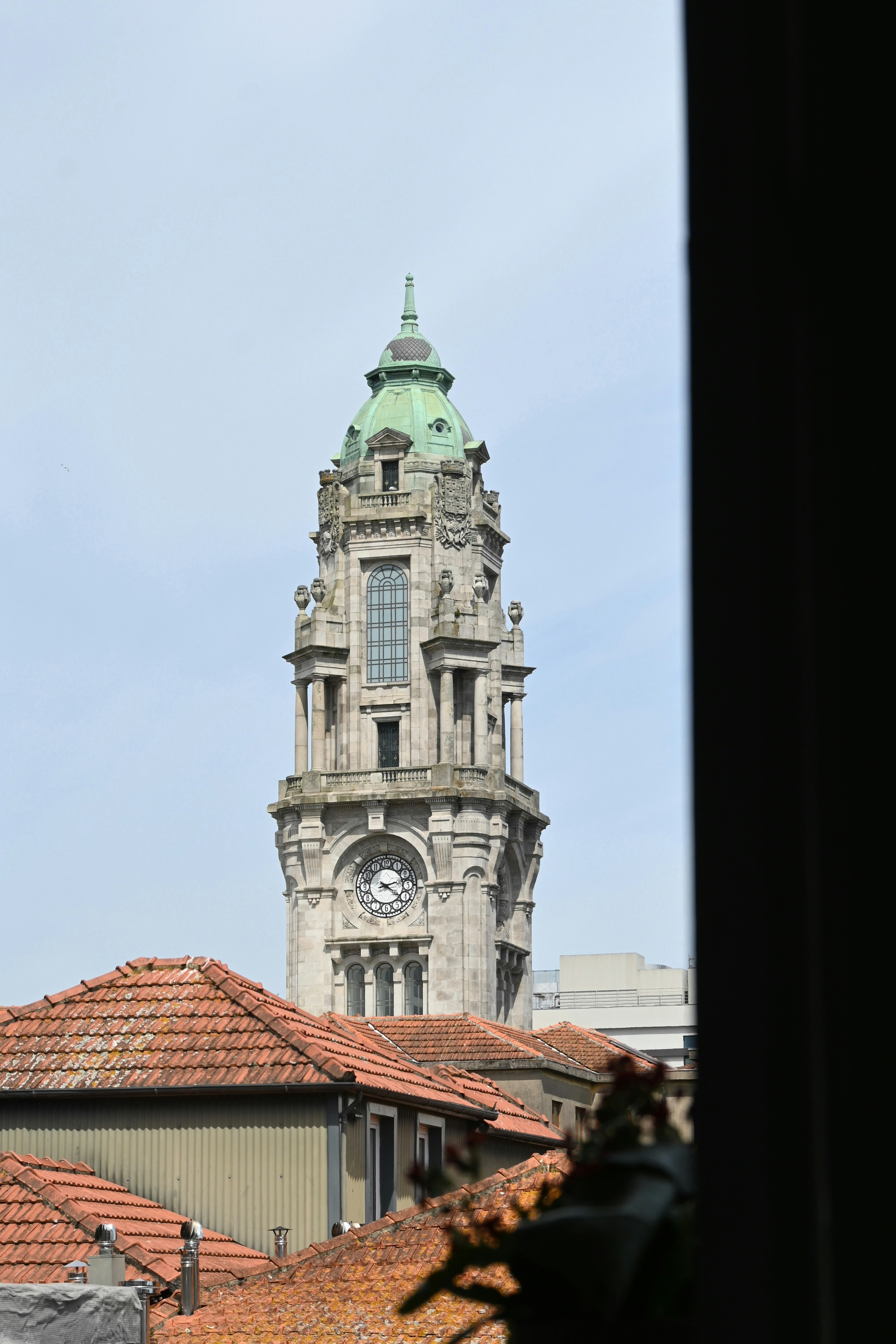 Clockwork Crown: Green-Domed Tower Rising Above Red Rooftops